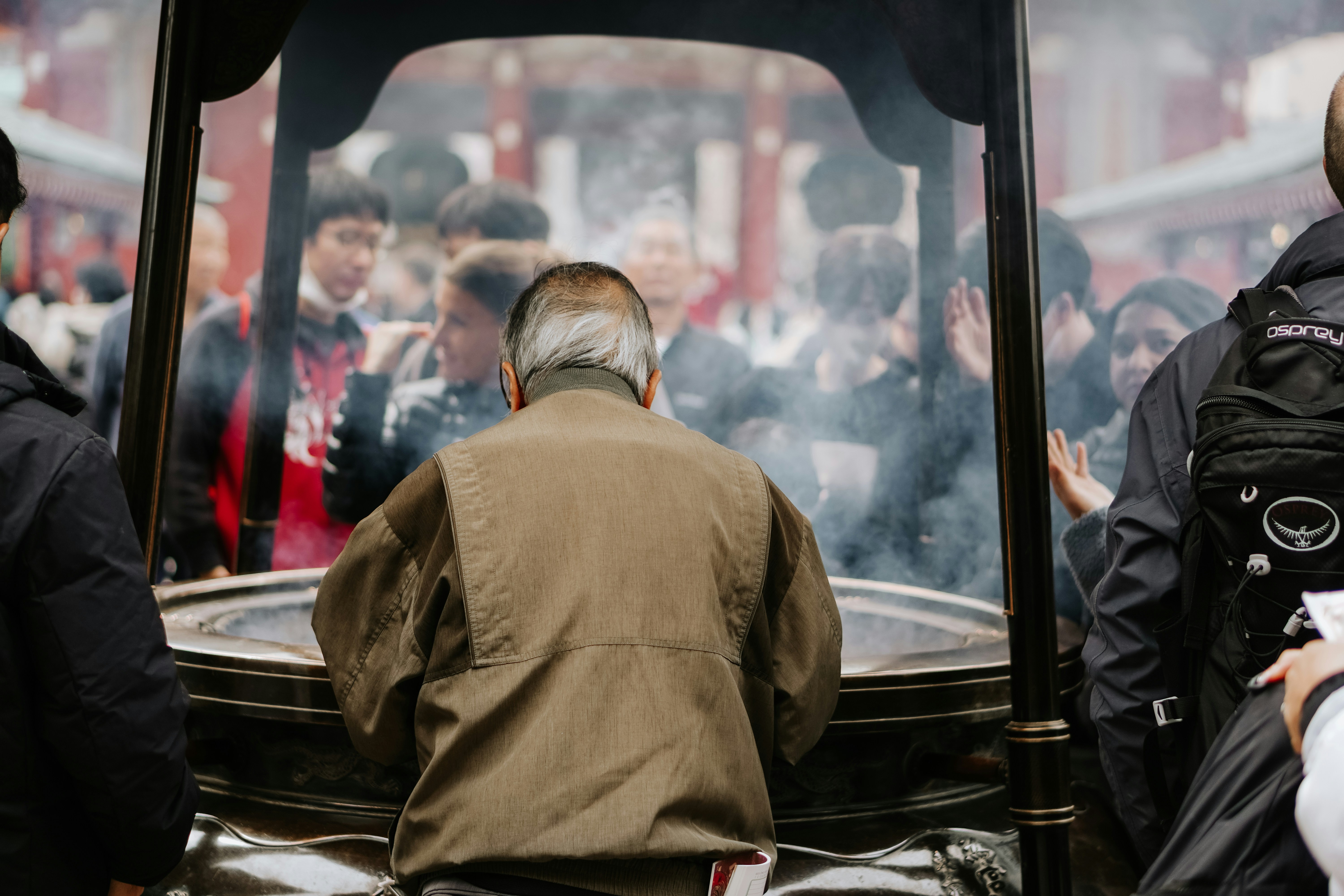 A person offers incense at a religious shrine.