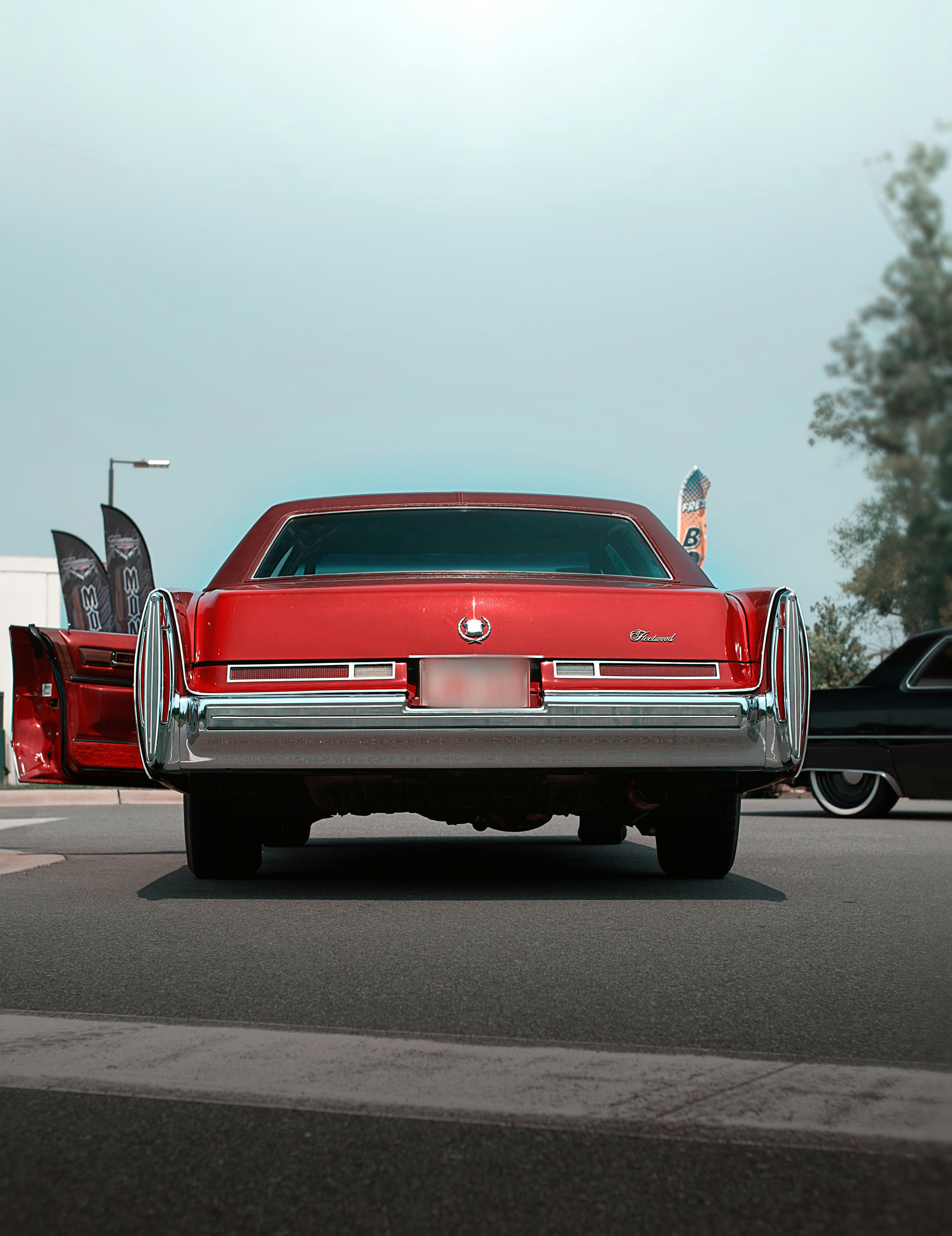 Rear Siren of Chrome: Red Cadillac at a Sunlit Car Show