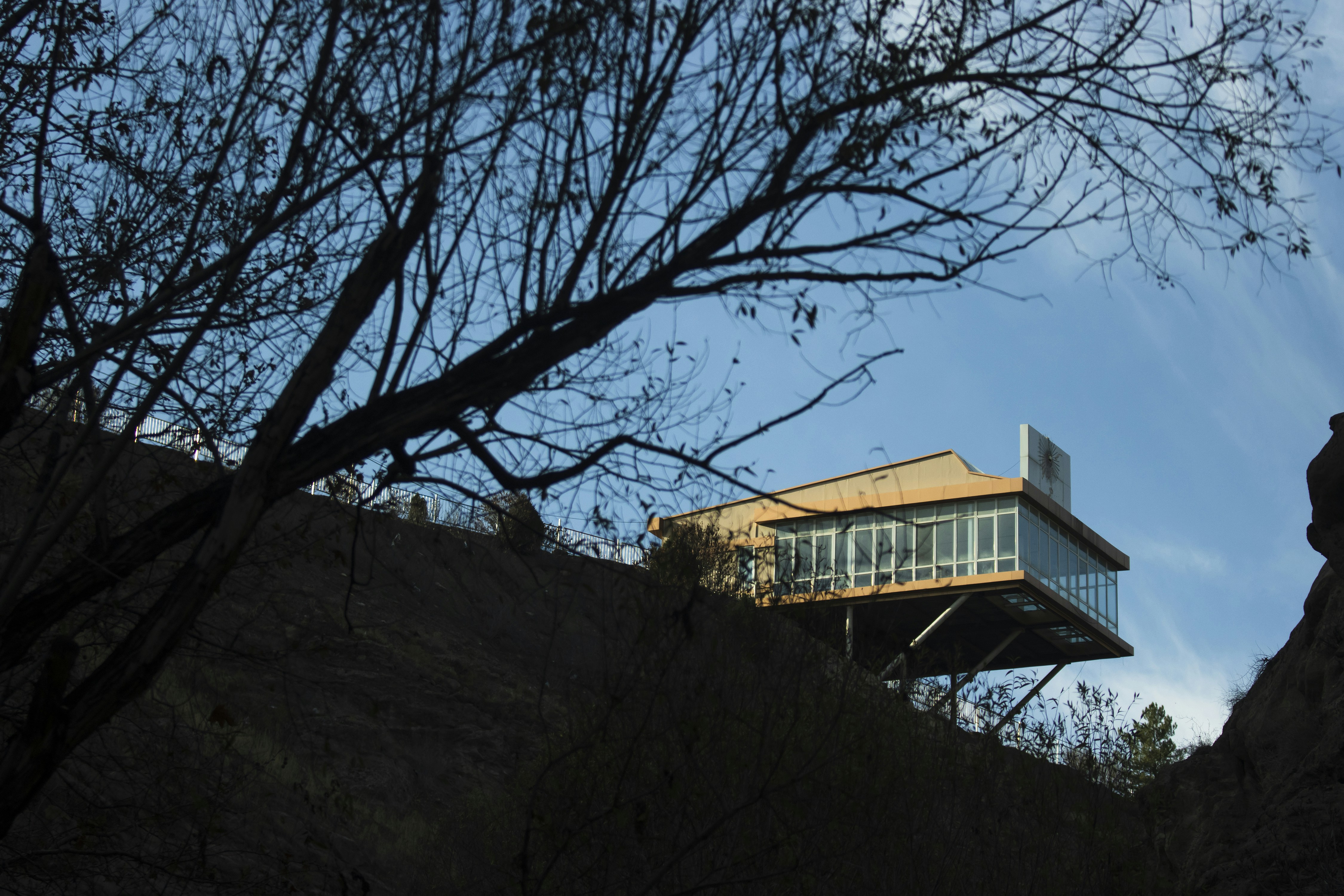 Perched Glass Pavilion Above a Cliff Under a Clear Blue Sky