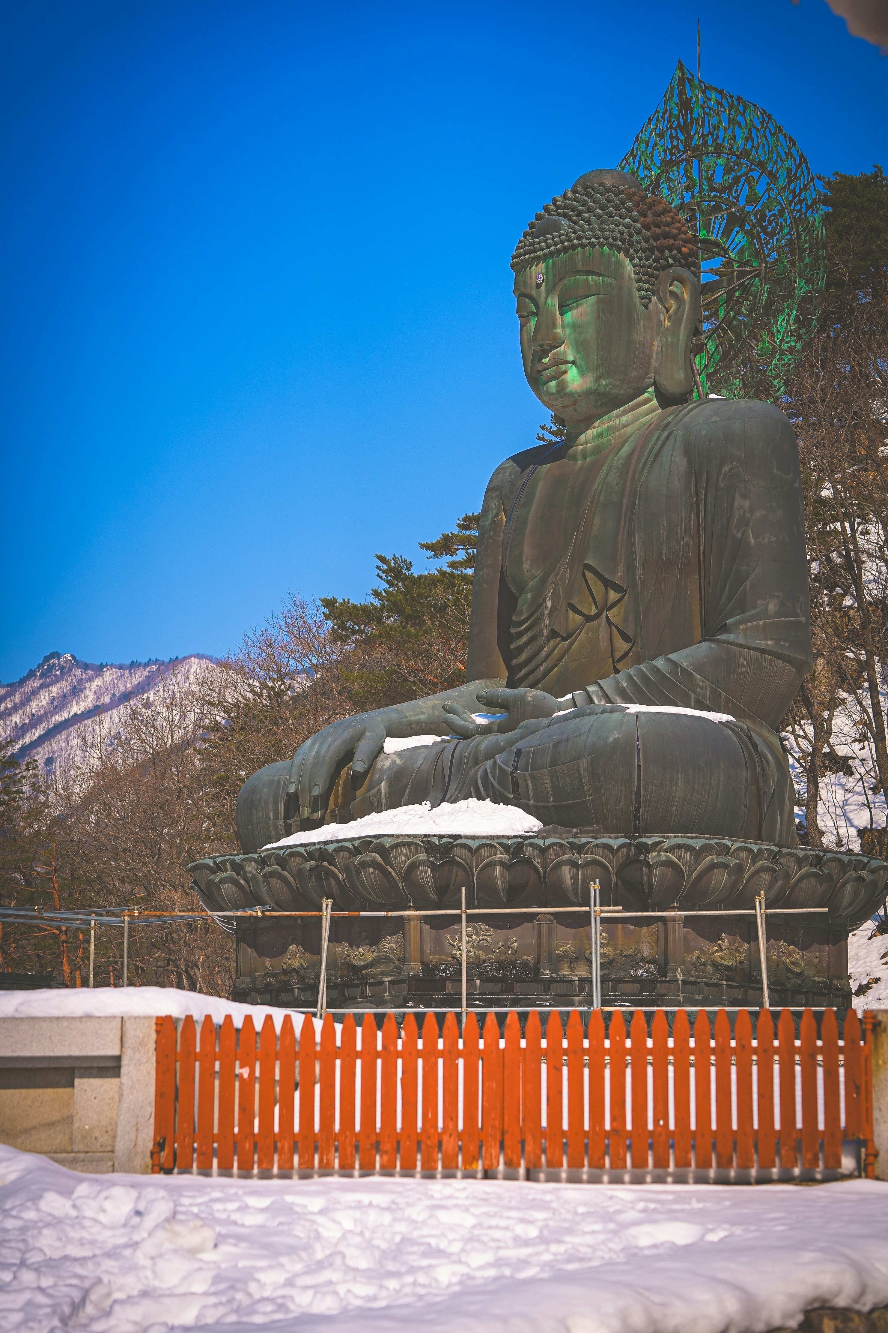 Snow-Crowned Guardian: A Meditative Buddha Beneath a Cerulean Winter Sky