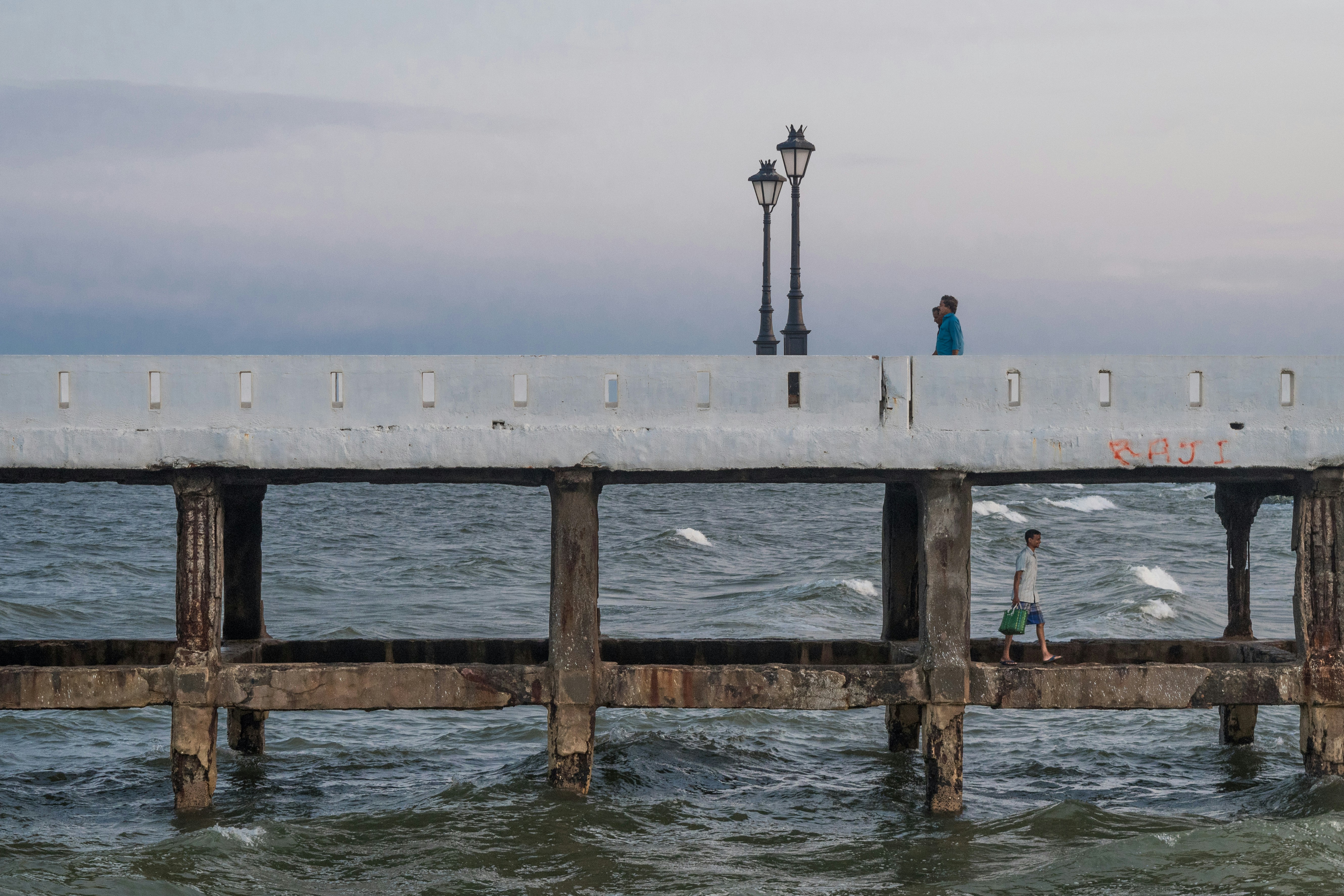 Pier at Dusk: A lone figure and a child on the weathered jetty