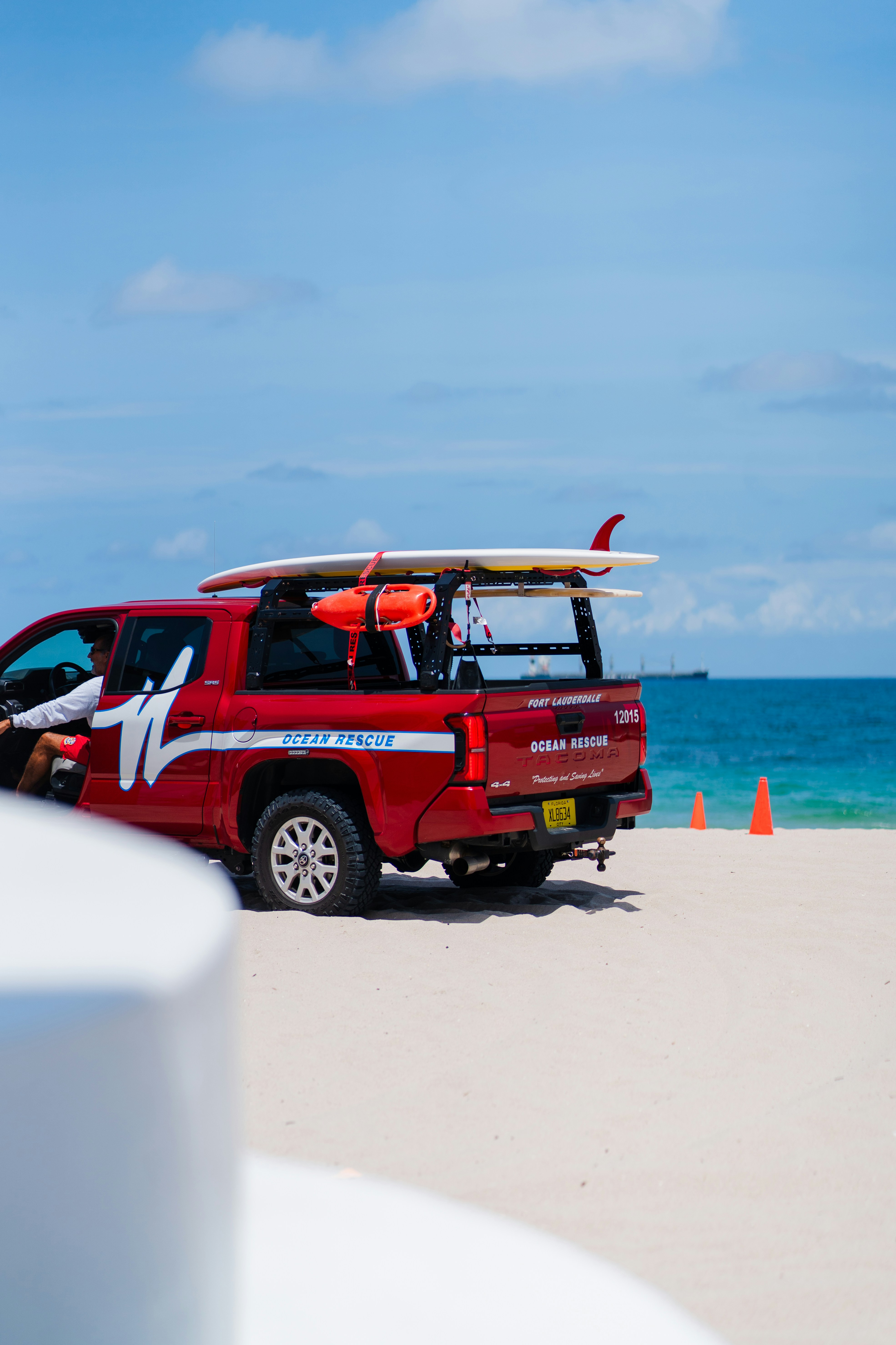 Red Ocean Rescue Truck on a Sunlit Beach, Surfboards Ready by the Shore