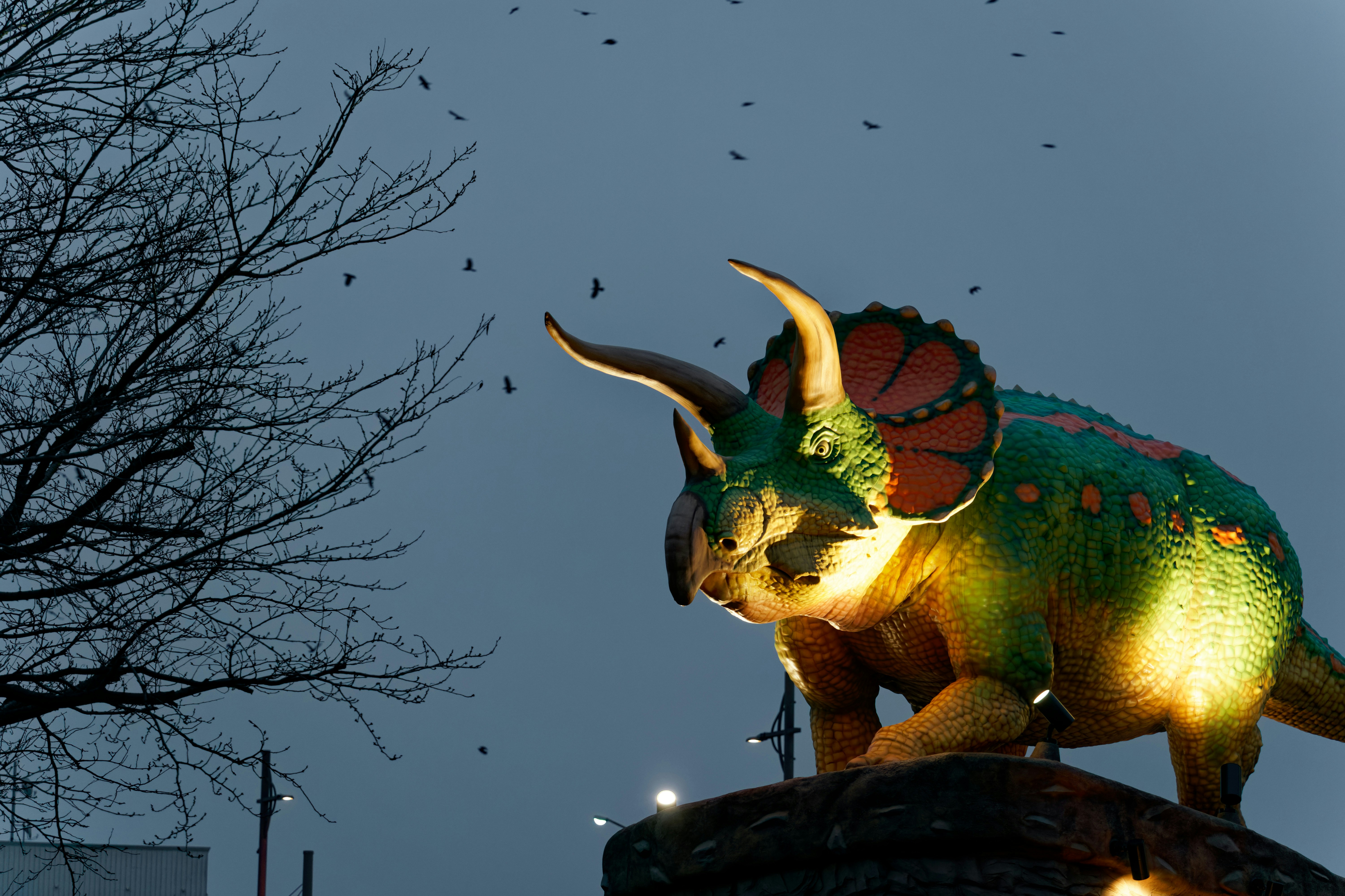 Night-Lit Horned Sentinel: Neon-green Triceratops guarding a rocky pedestal at dusk
