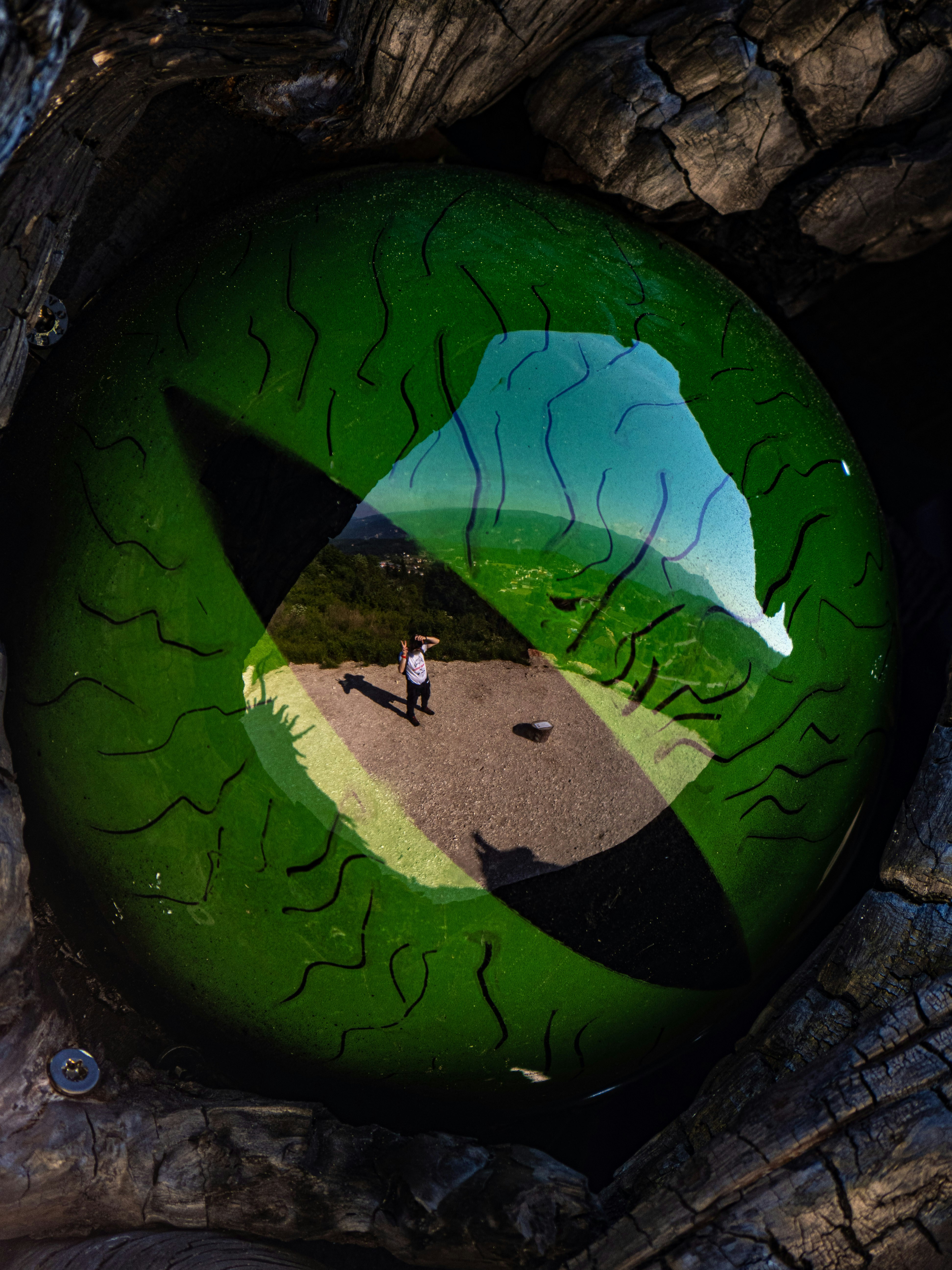 A green eye reflects the landscape and person.