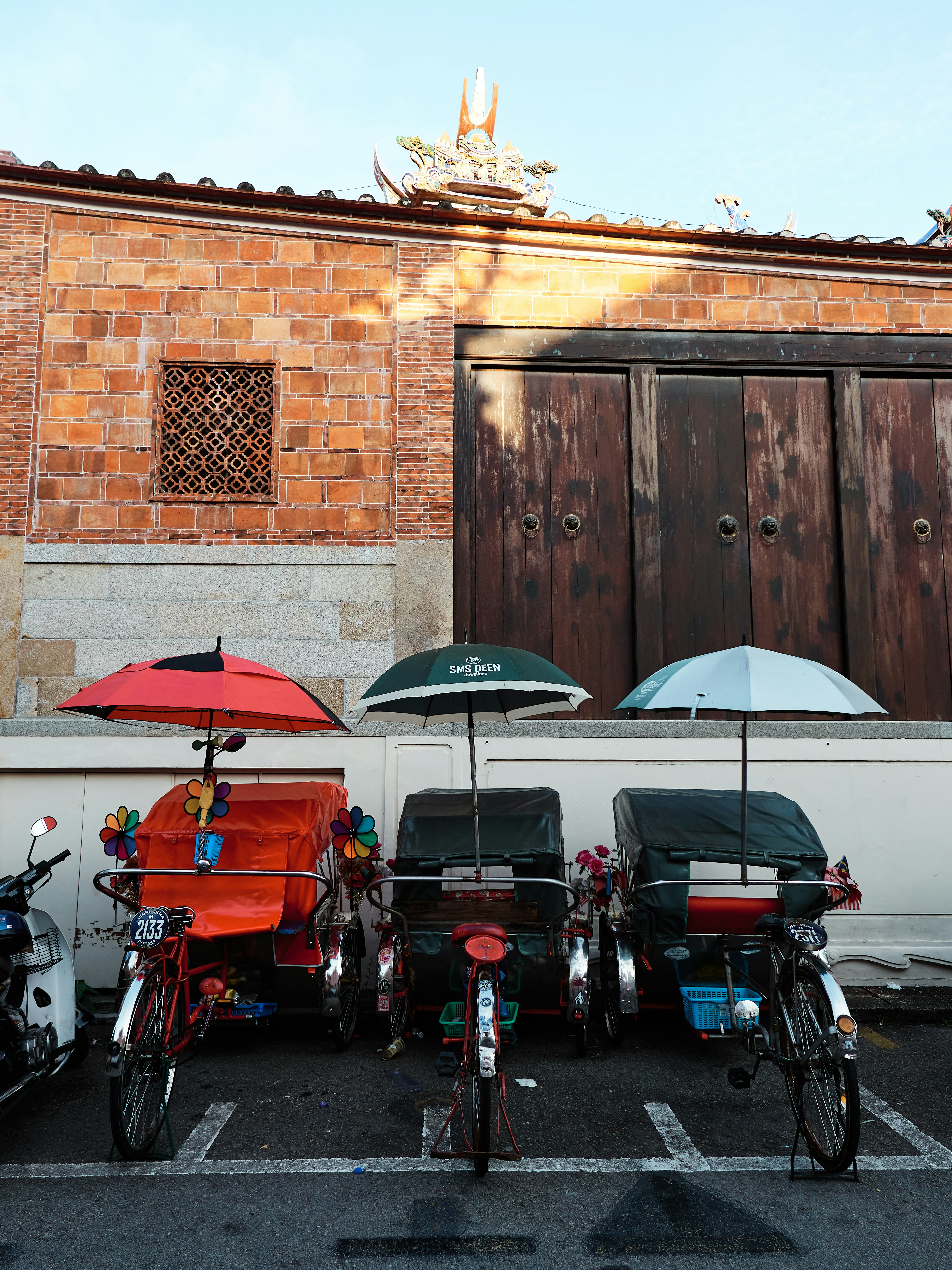 Three colorful rickshaws are parked in front of a building. photo ...