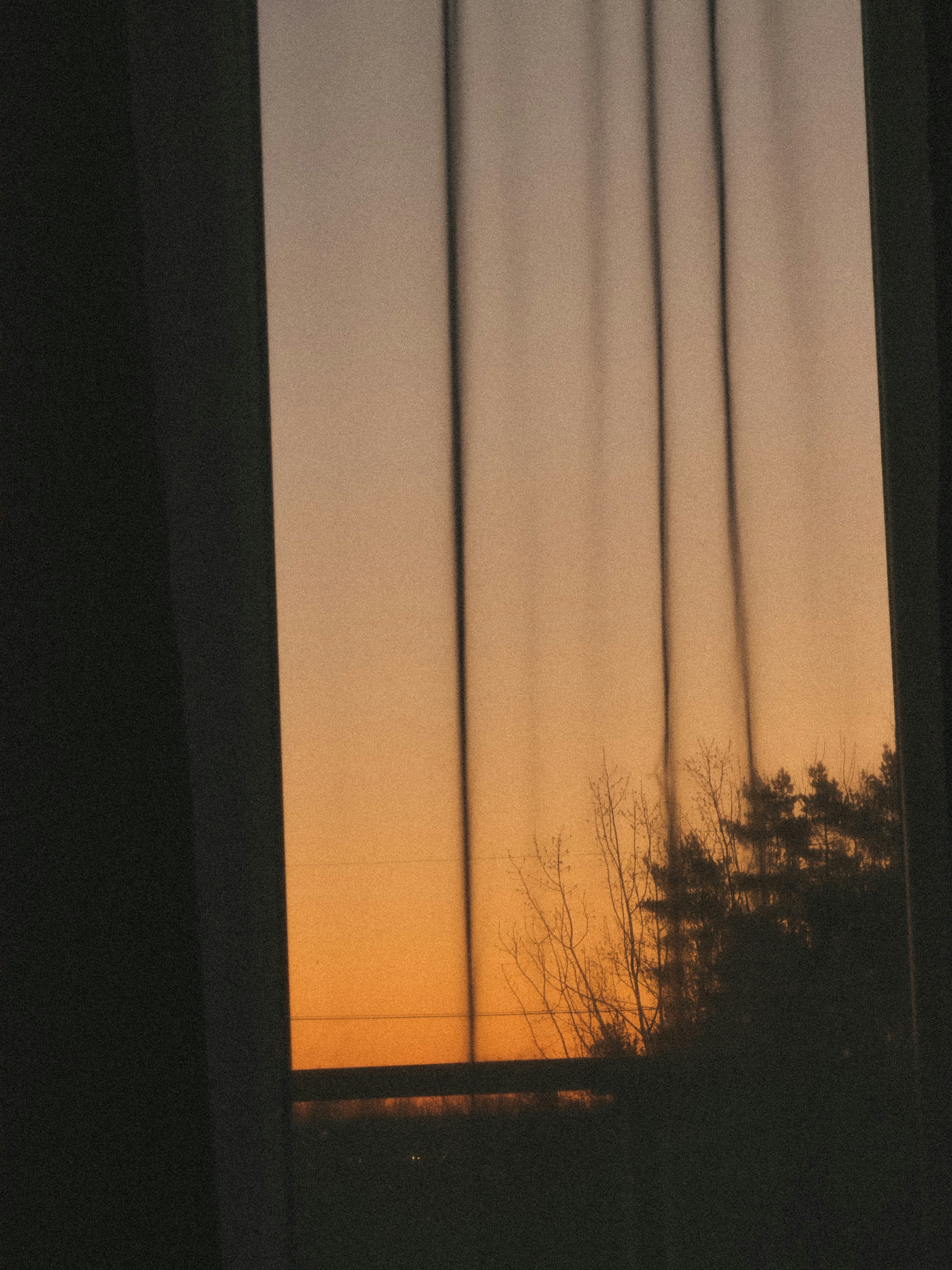 Sunset peeks through a window and curtains.
