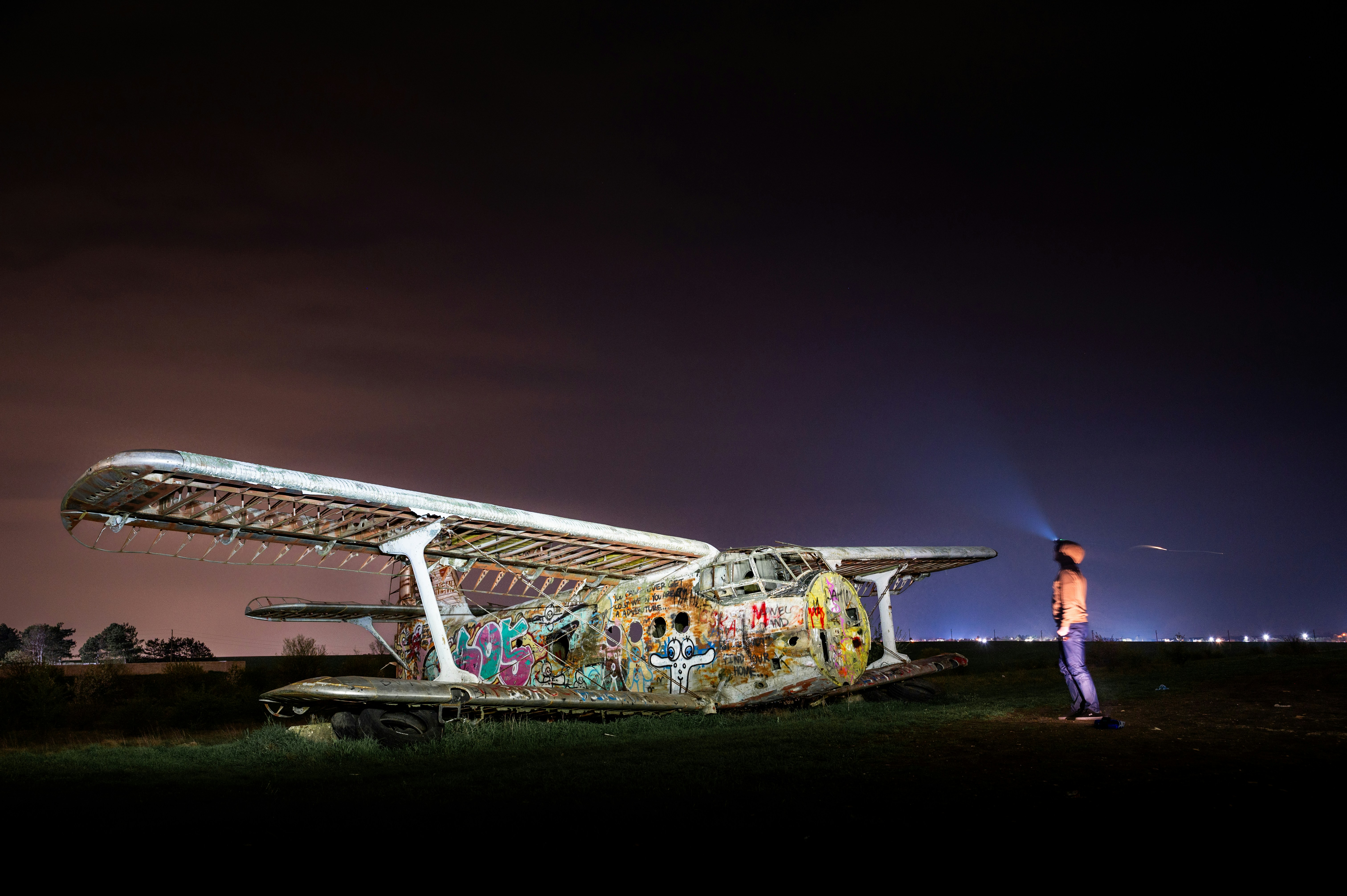 Luminous Graffiti Wreck: A Night-Airplane Remnant Under Lone Spotlight