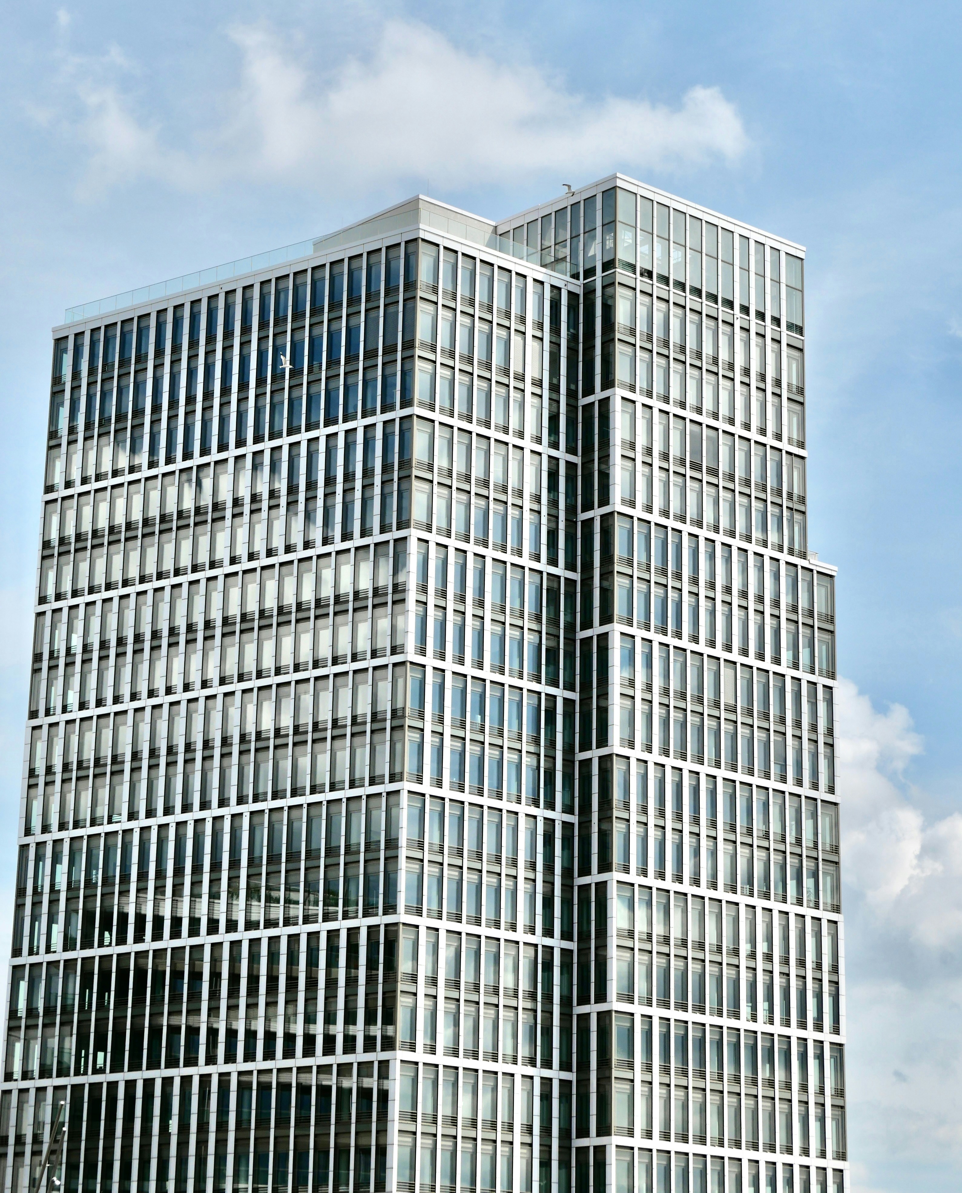 A contemporary glass skyscraper reflecting the sky, showcasing its sleek architecture and vertical lines.