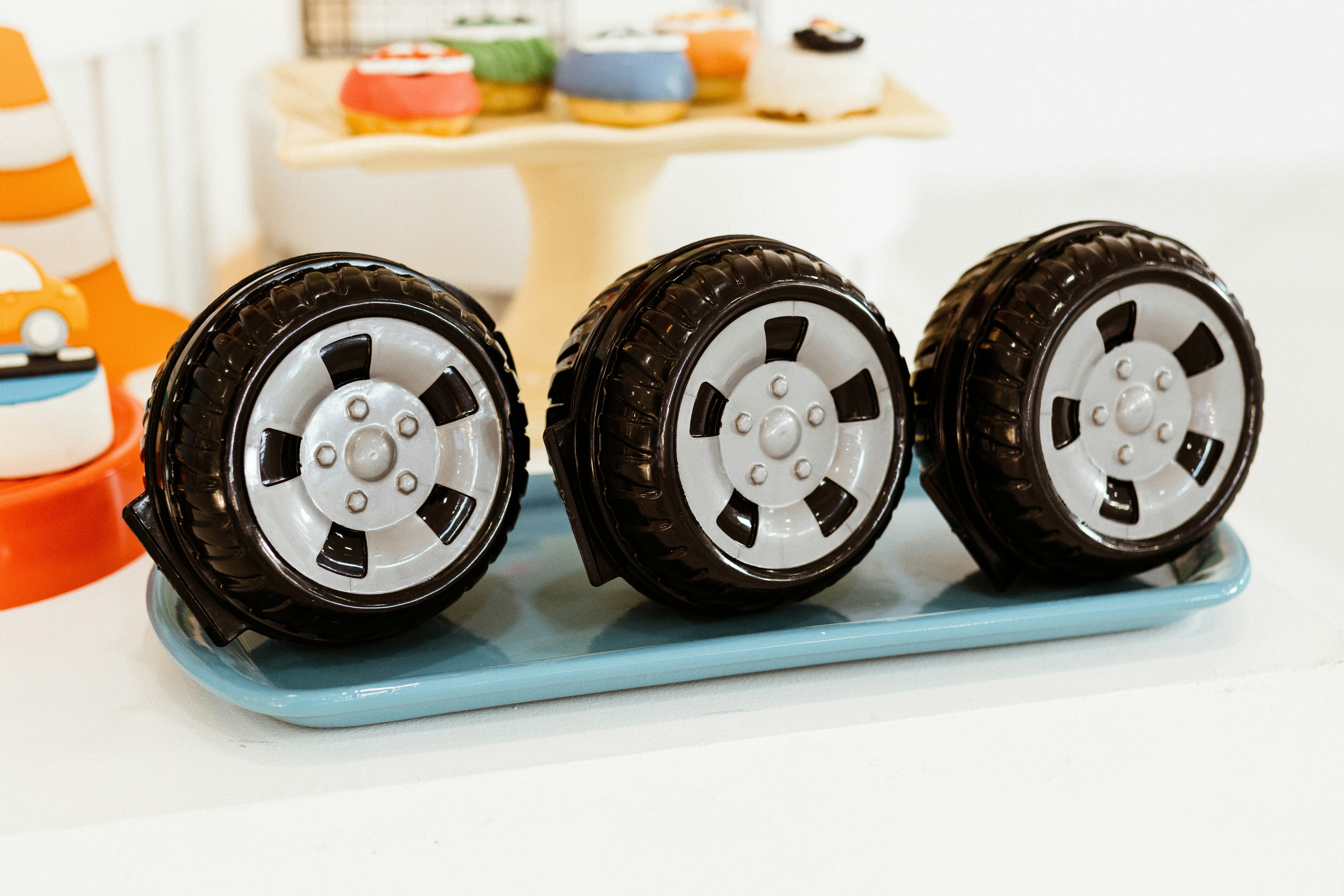 Playful Trio: Toy Car Wheels Rest on a Pastel Blue Tray