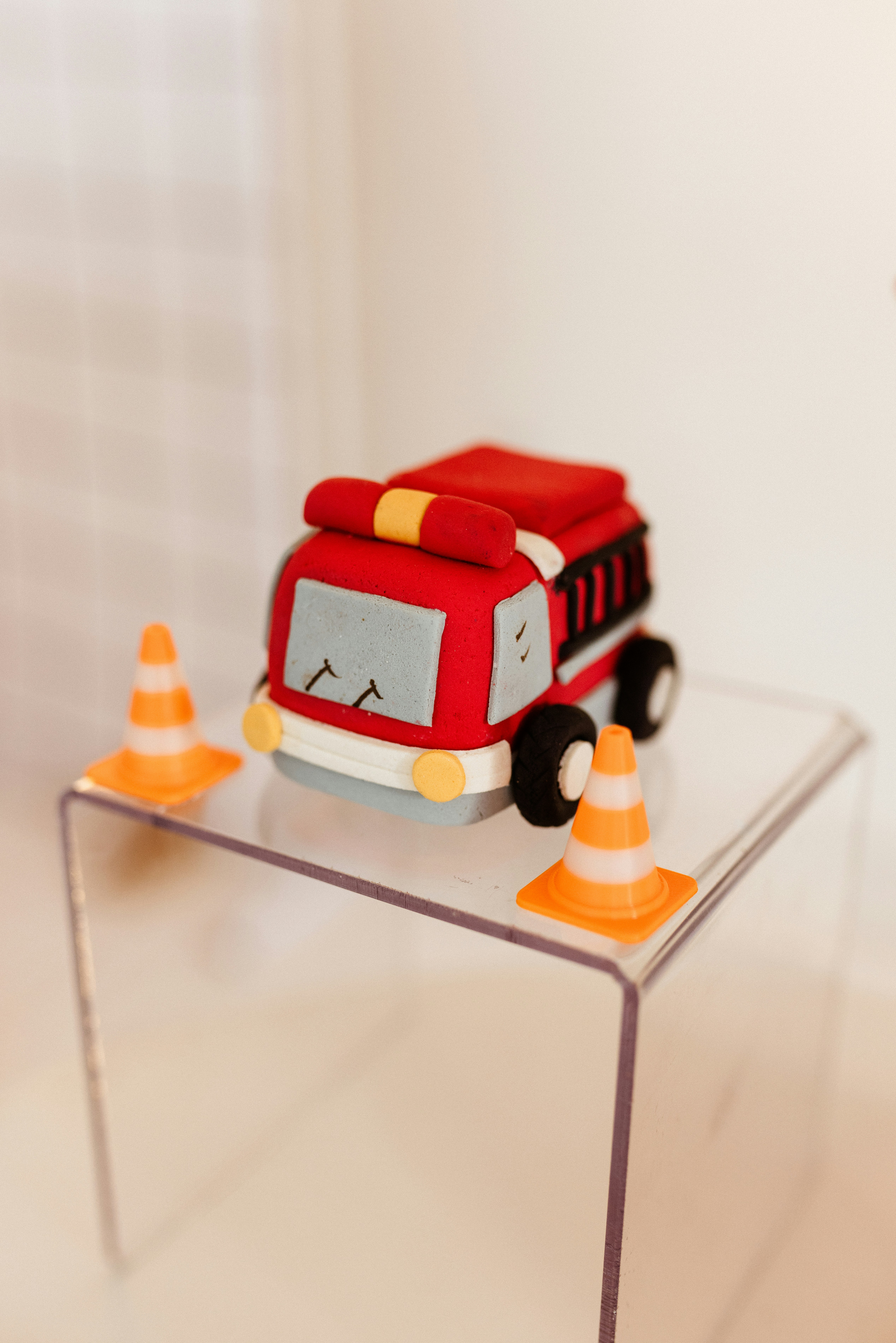Tiny Fire Engine on Display: A Playful Model Surrounded by Orange Traffic Cones