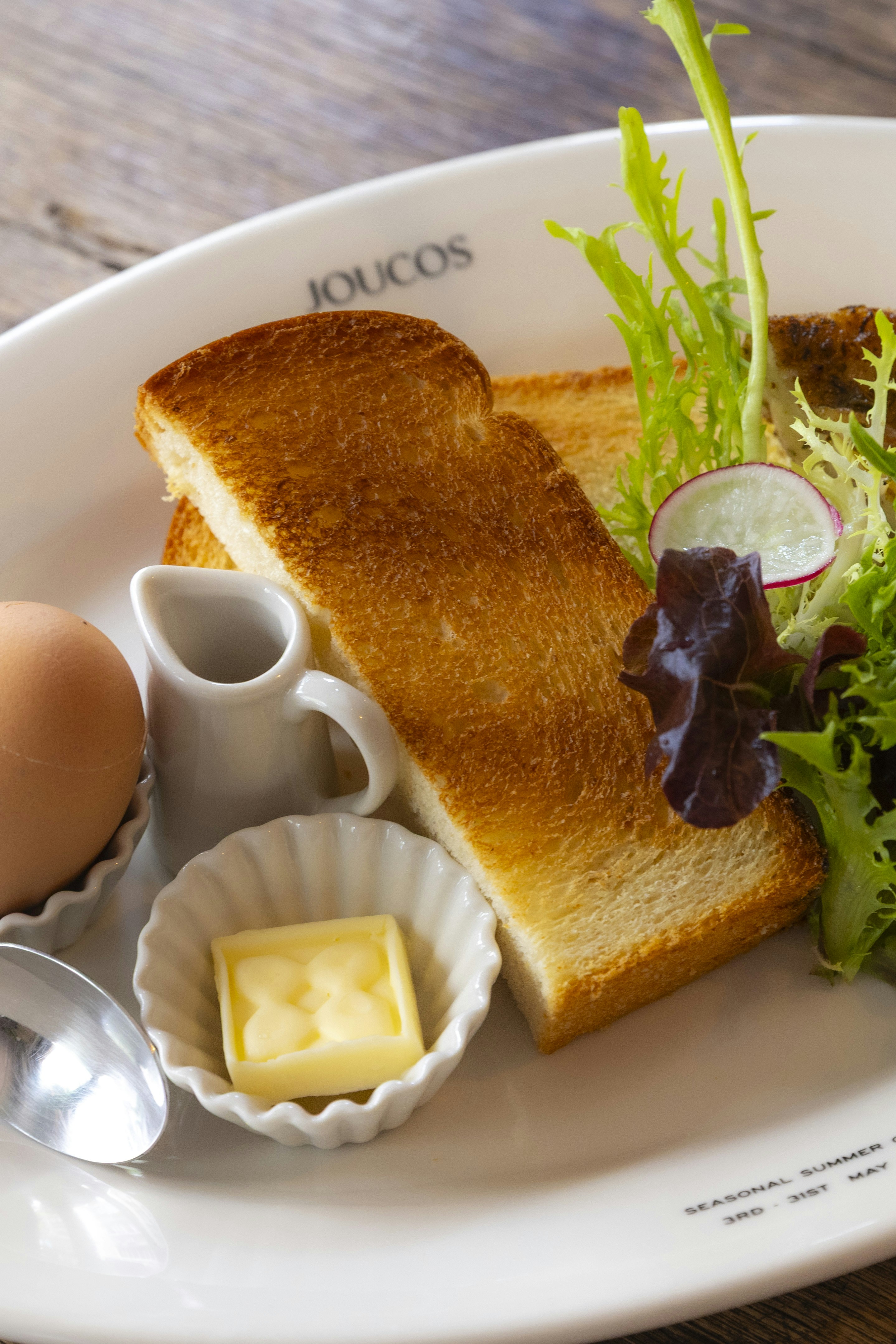 Breakfast of toast, egg, salad, and butter.