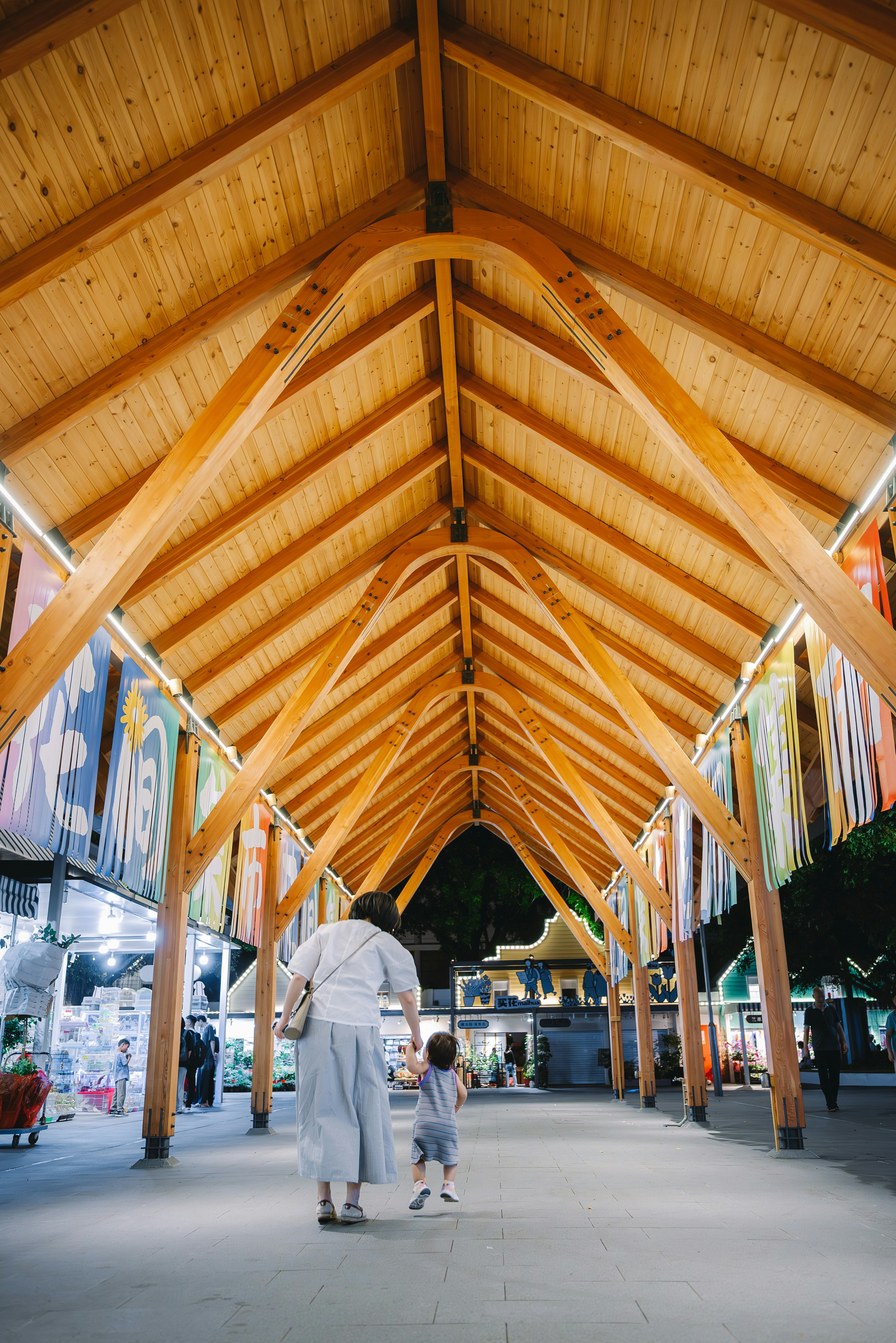 A woman and child walk underneath wooden beams. photo – Free Woman ...