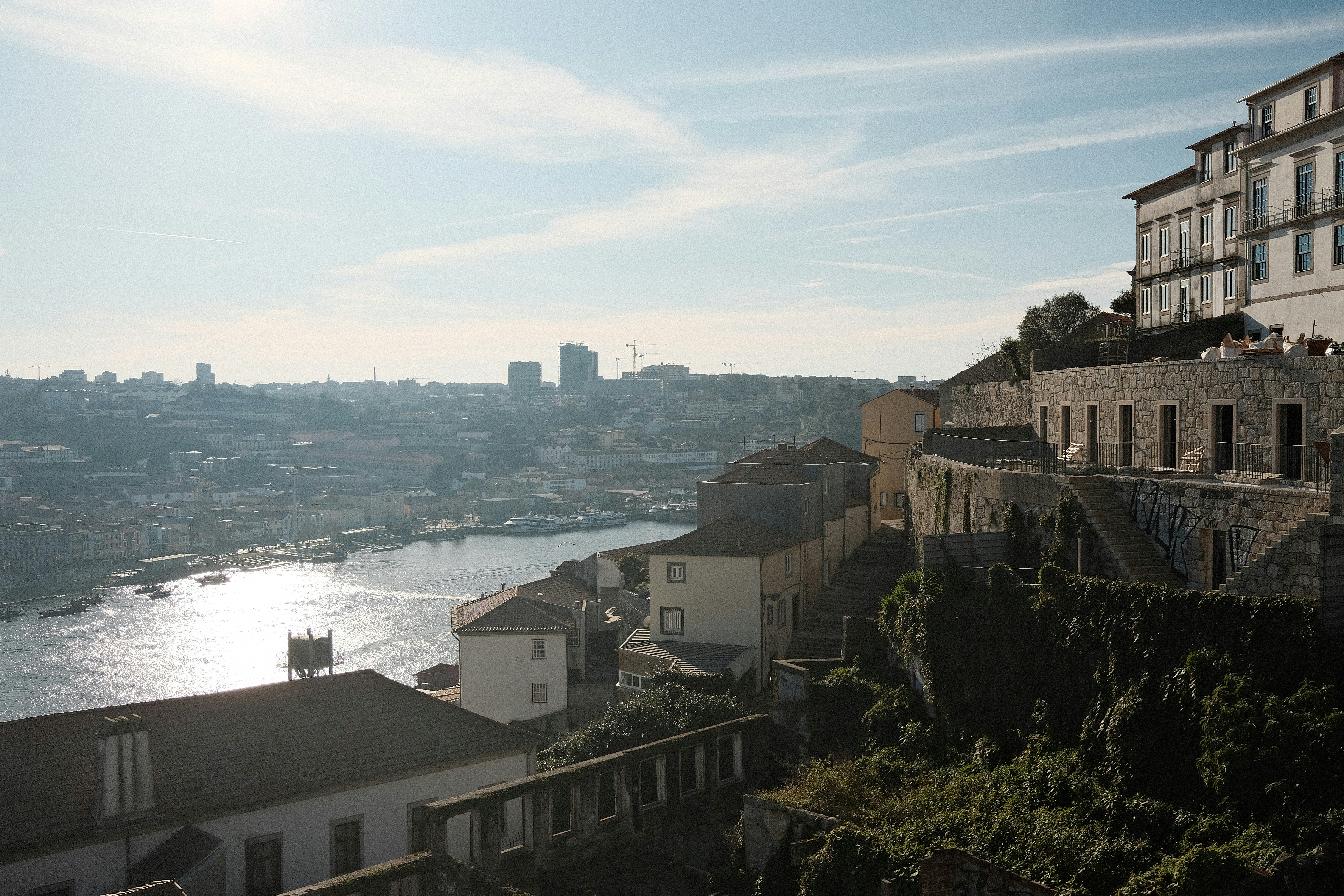 Scenic view of Porto's riverside, showcasing historic architecture and the shimmering Douro River under a clear sky.