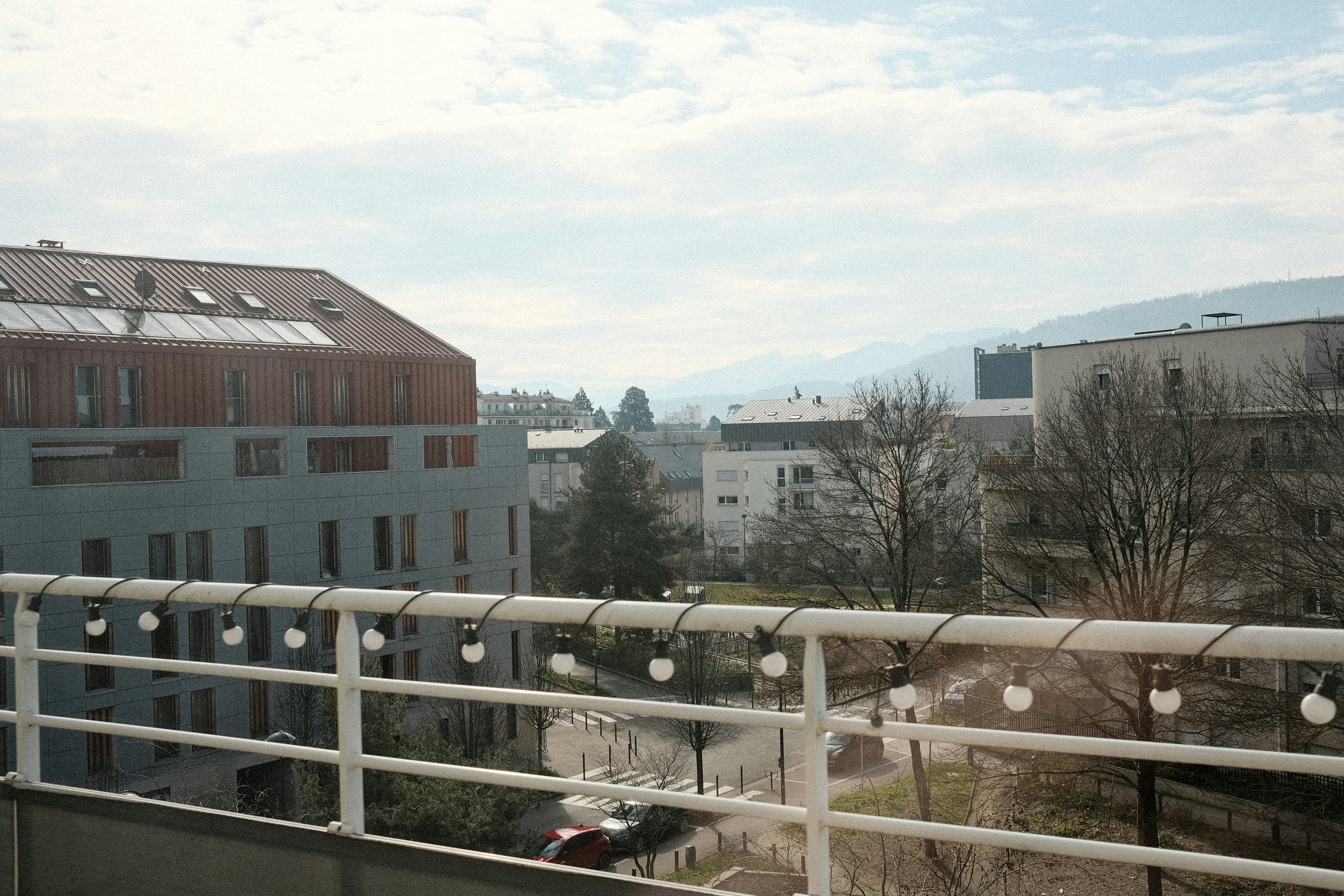 Balcony view showcasing modern architecture and a serene urban landscape under a cloudy sky.
