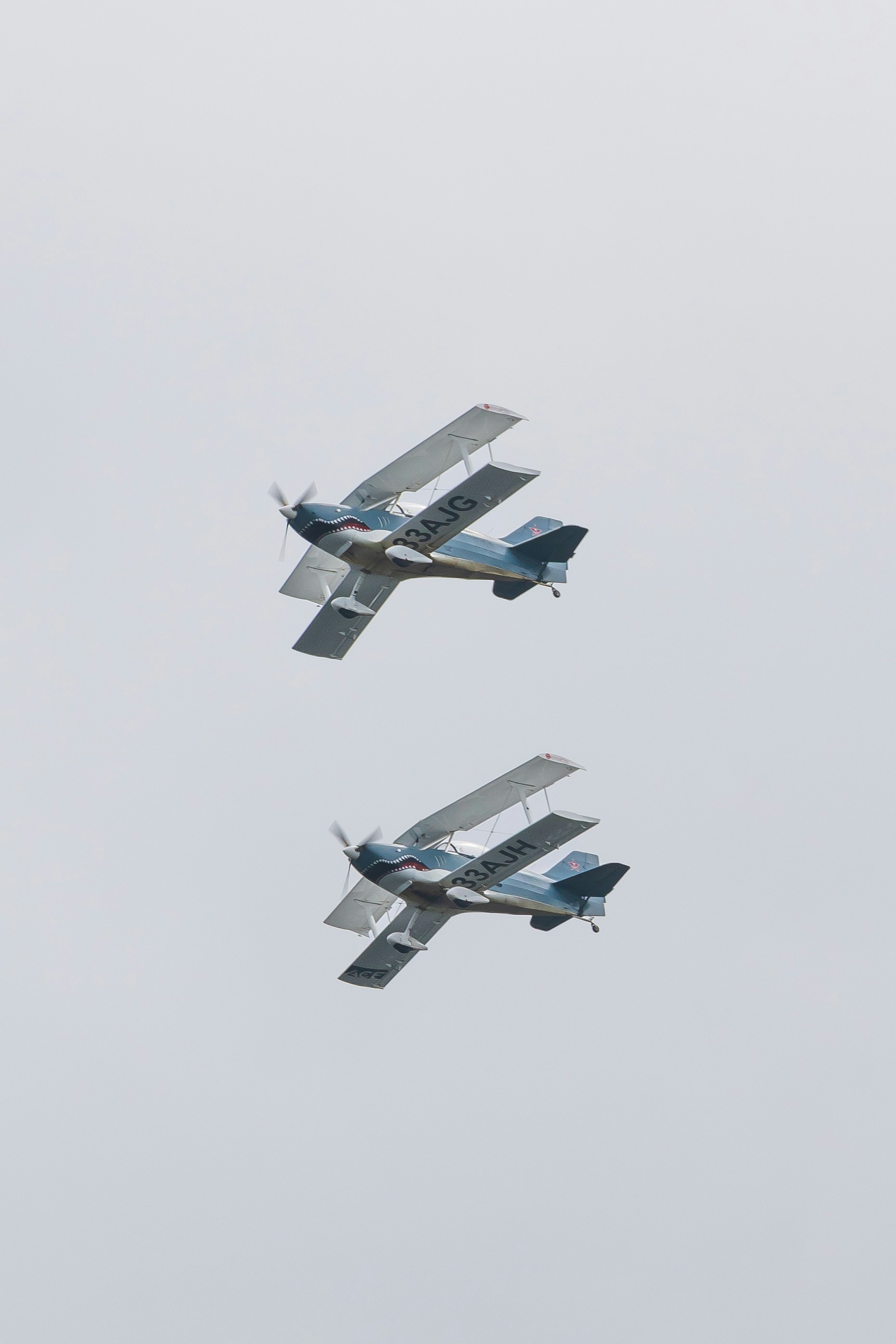 Two biplanes flying in formation against a cloudy sky. photo – Free Airshow Image on Unsplash