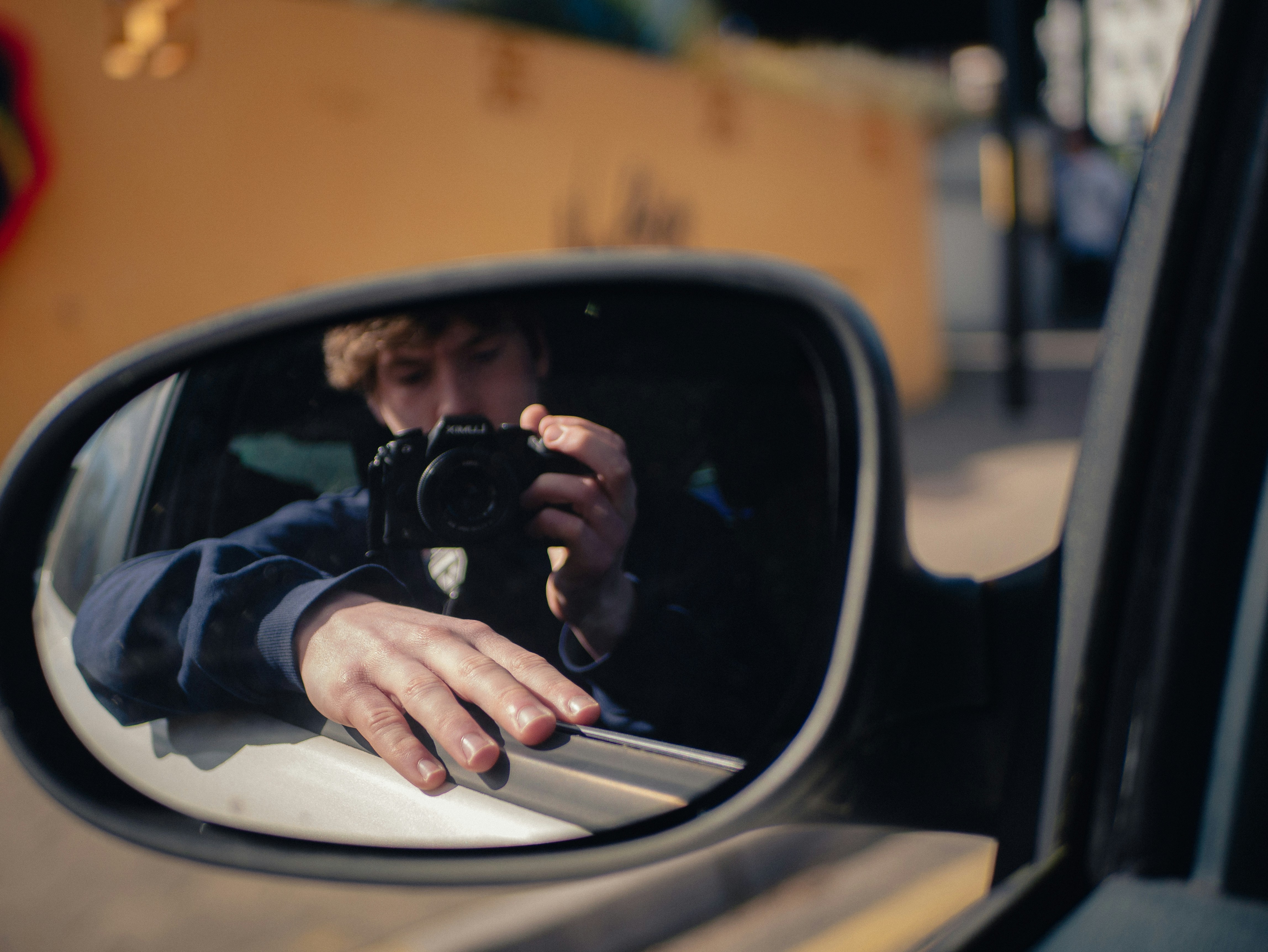 Reflected Focus: A Photographer Framing the Moment in a Car's Side Mirror