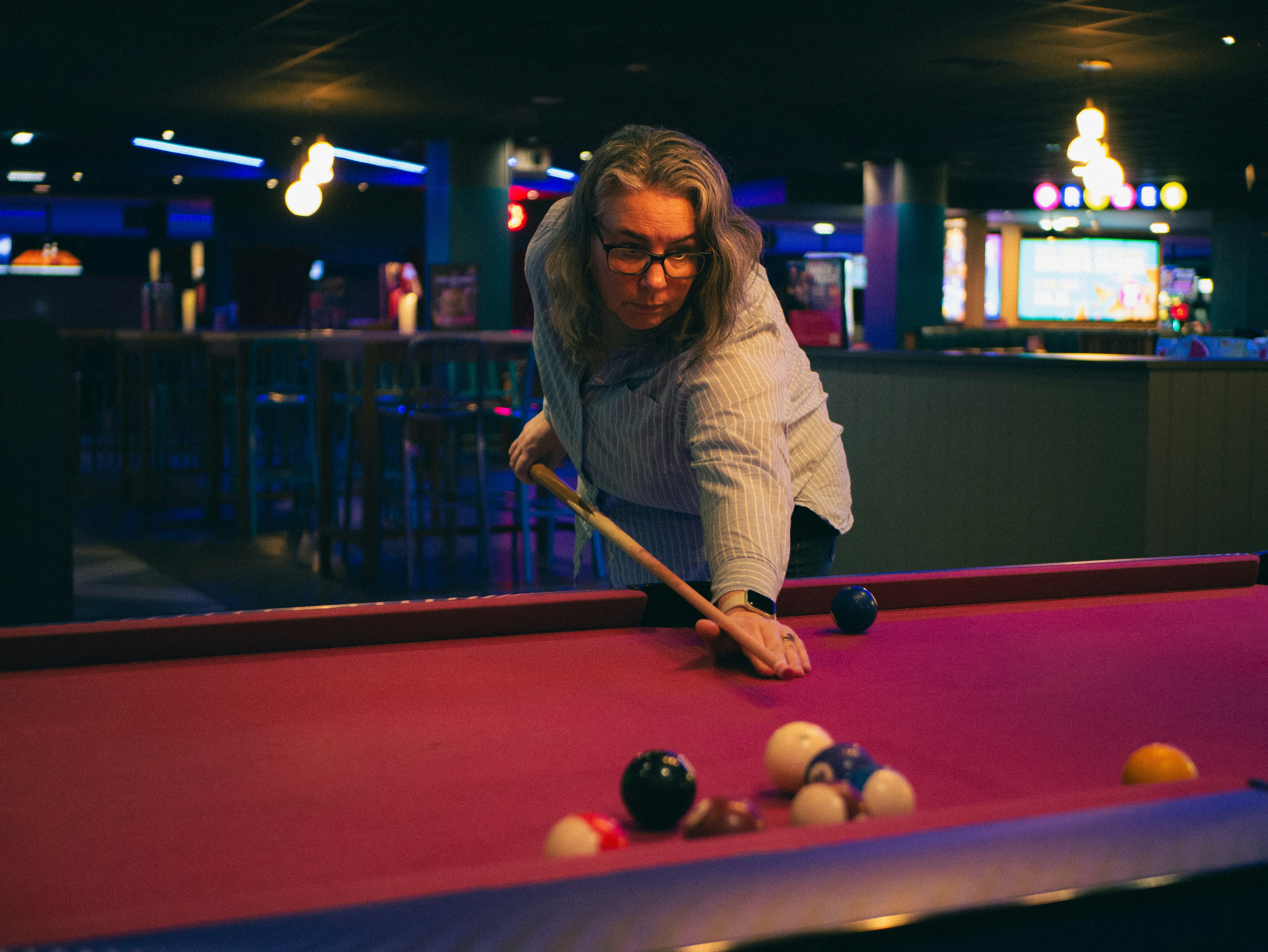 Neon Focus Over Red Felt: A Pool Shot Beneath Bar Lights