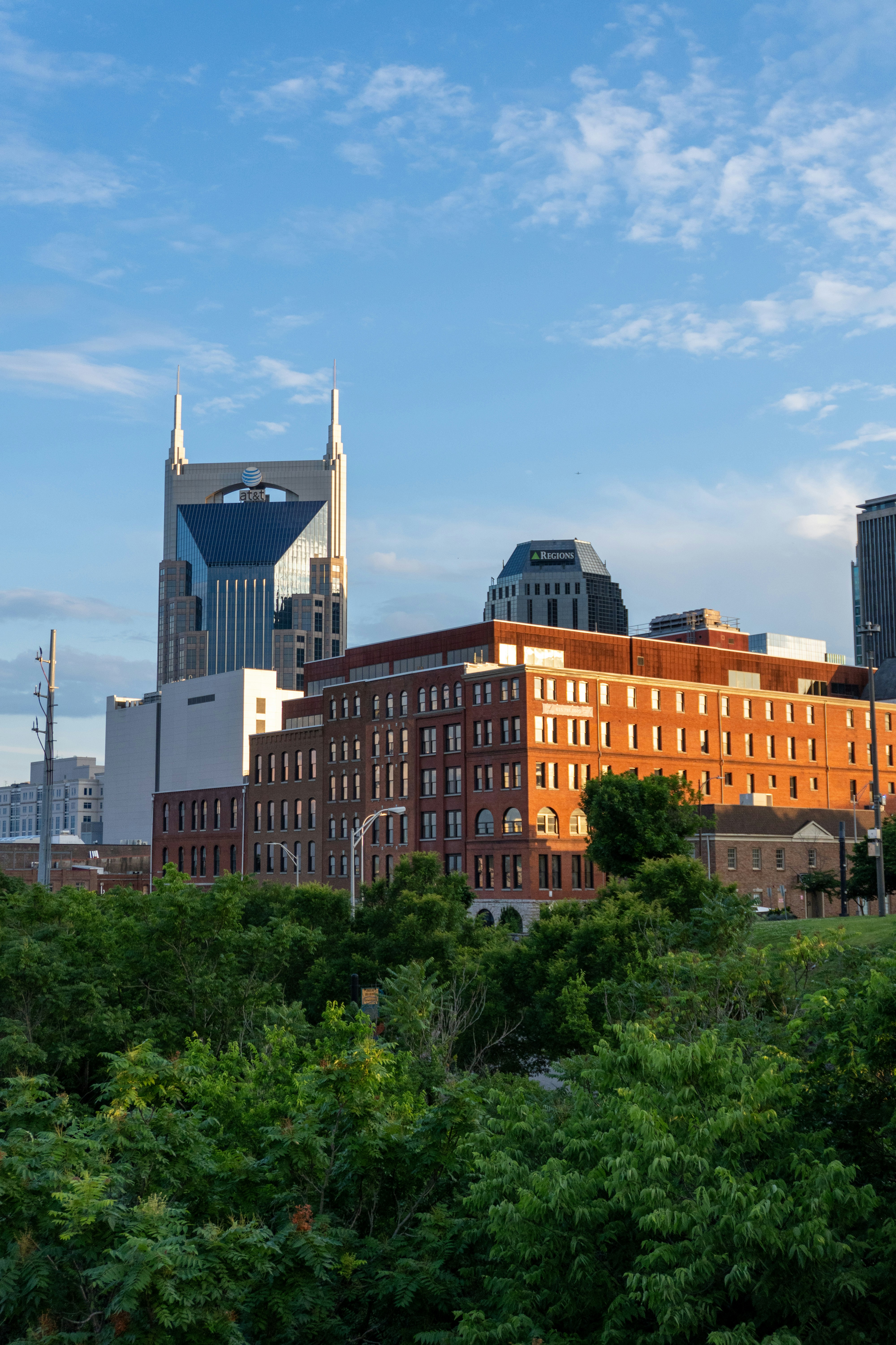 Brick, Steel, and Green: A Daylight Cityscape Framed by Foliage
