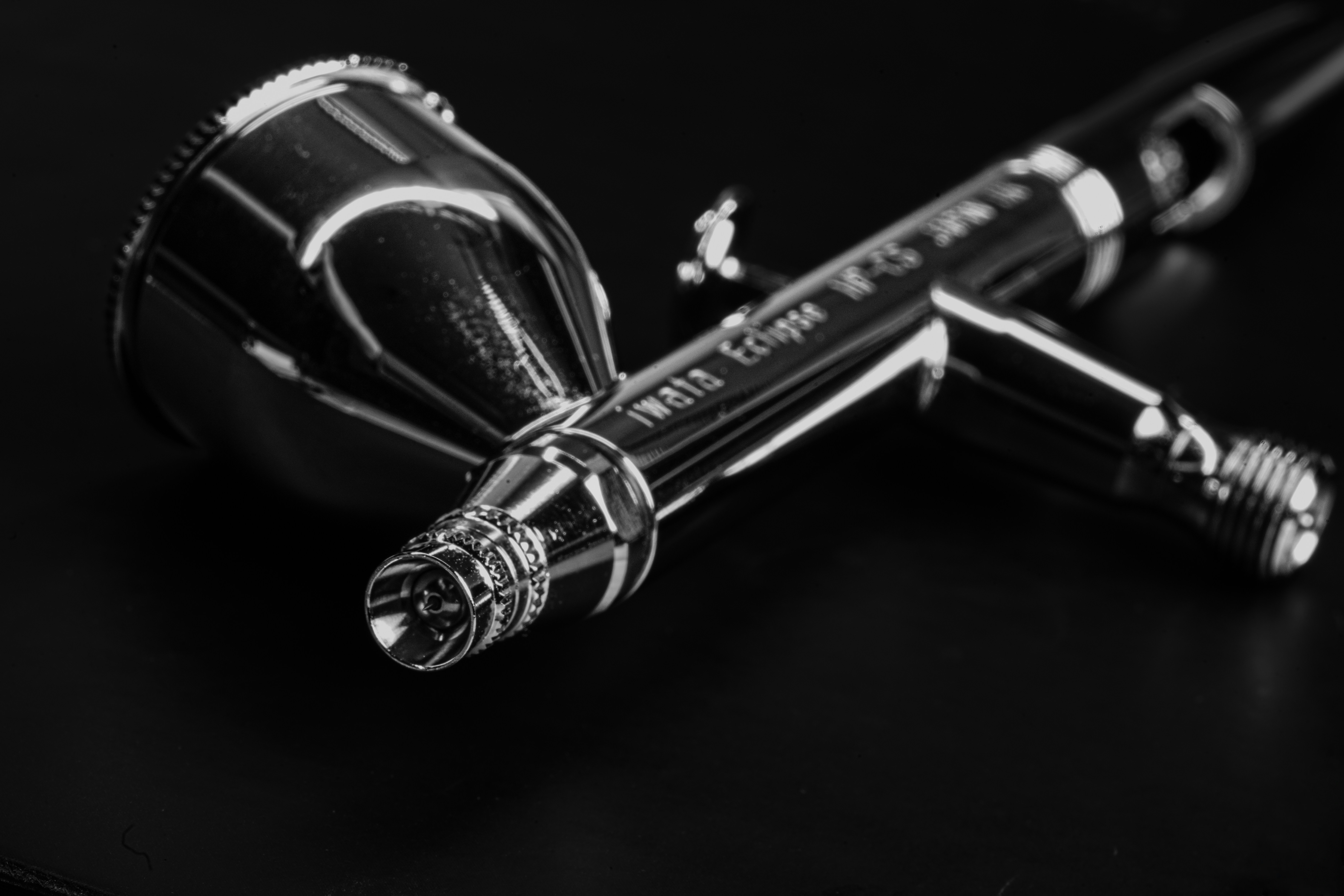 An airbrush rests on a dark surface.