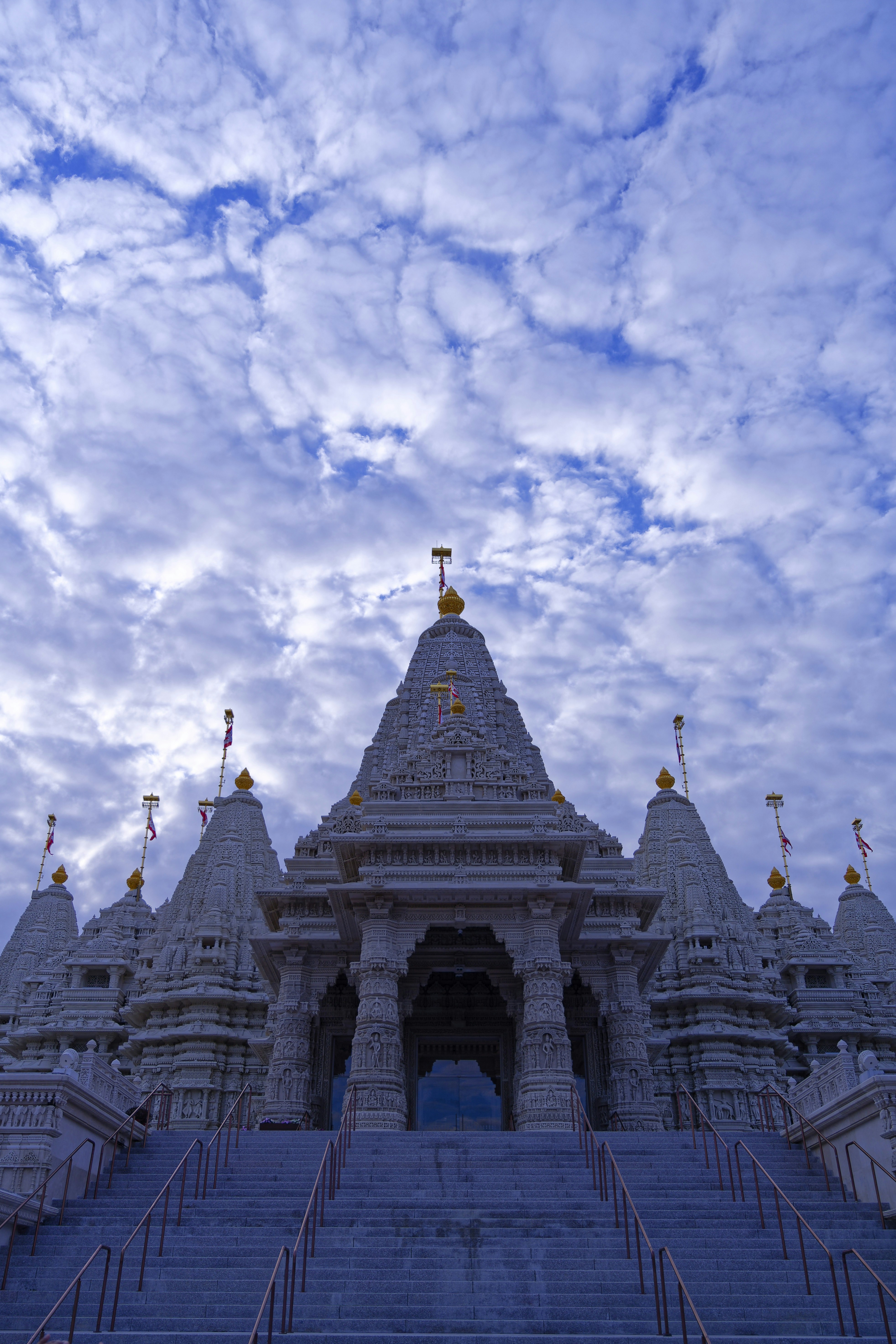Intricately carved temple entrance framed by a dramatic sky filled with clouds.