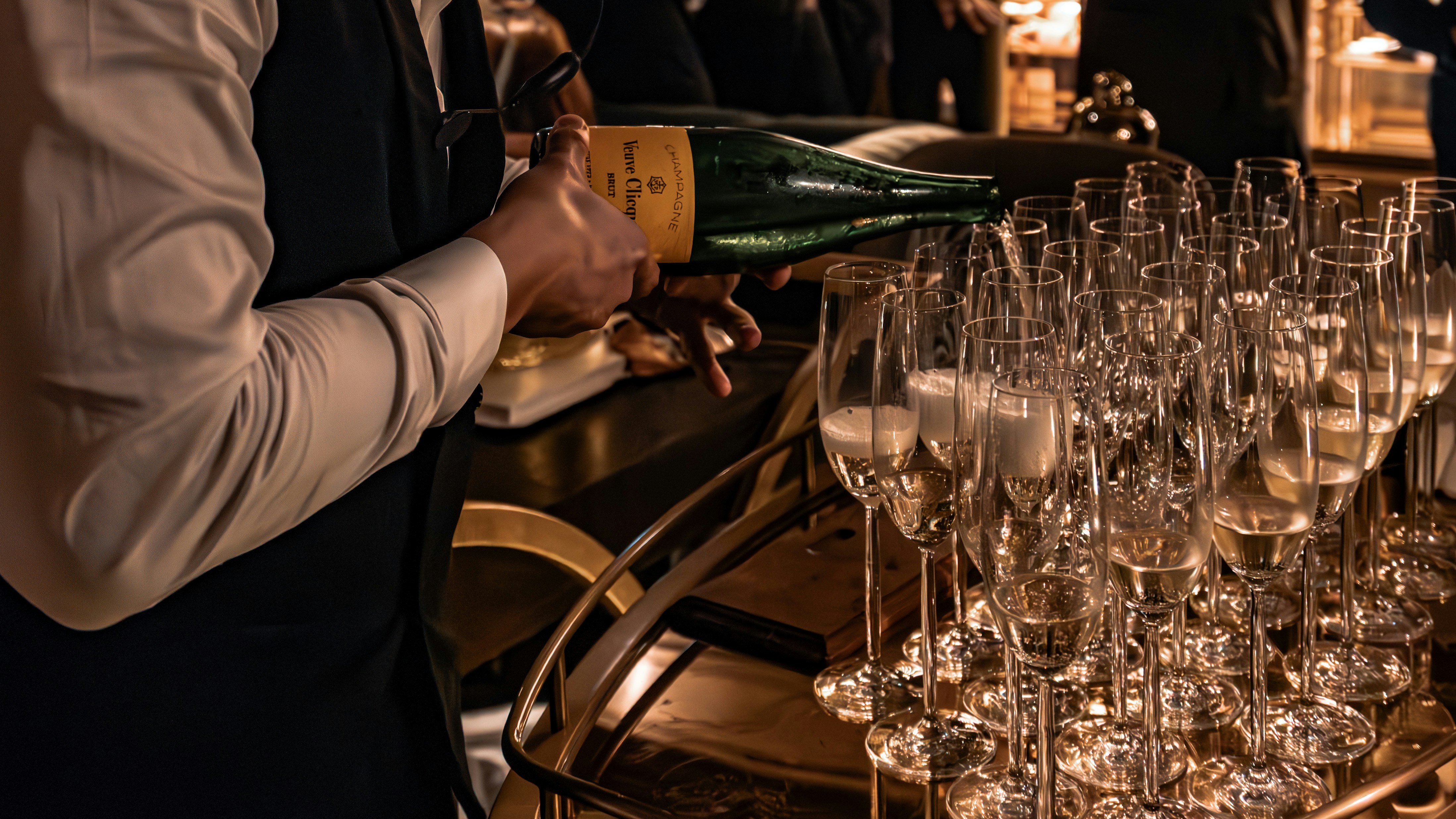 A server pours champagne into a cascade of elegant flutes, capturing the essence of celebration and sophistication.