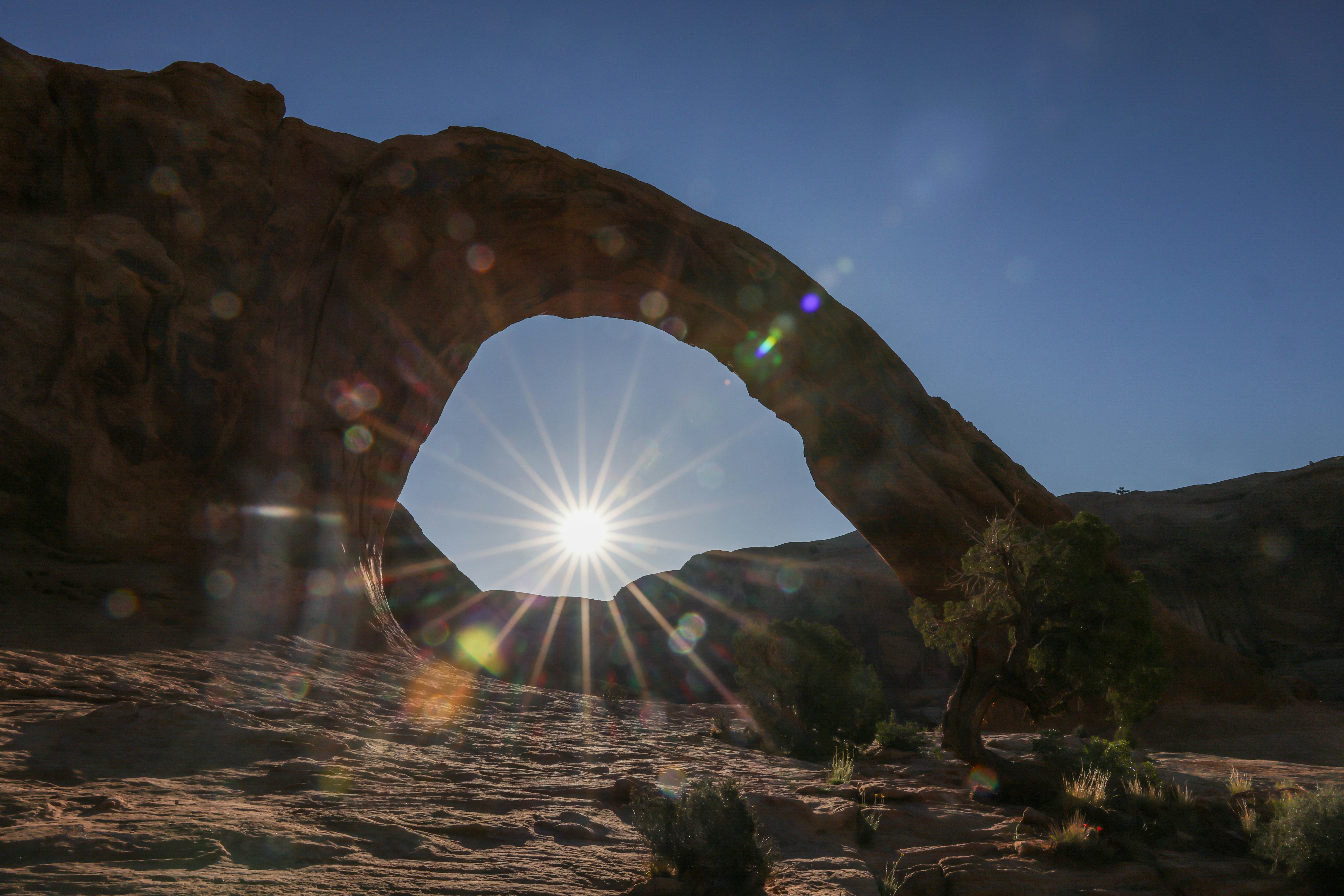 Sun shines brightly through an arch in the desert. photo – Free Sunrise ...