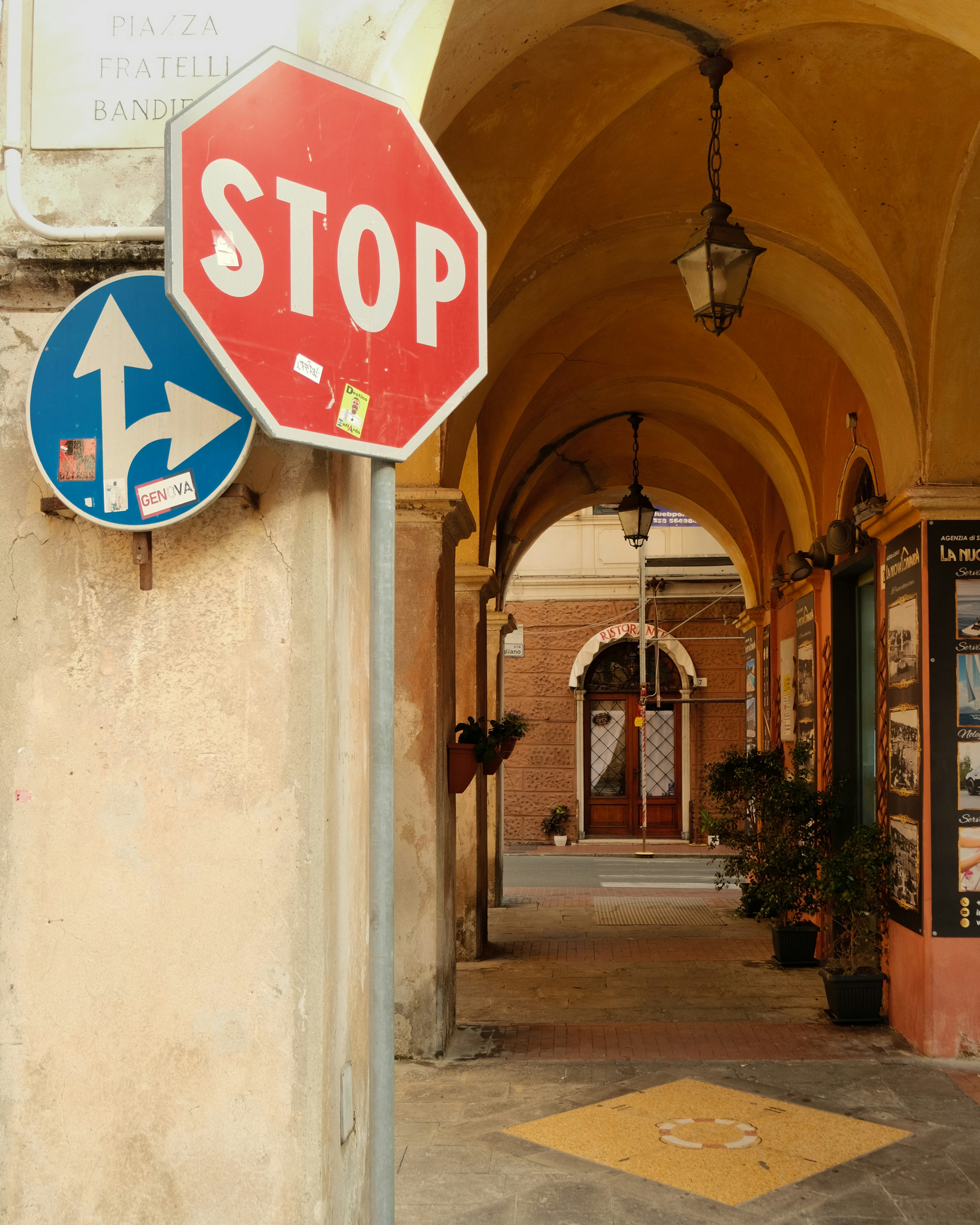 Stop Sign at the Sunlit Arcade: Lanterns, Arches, and a Quiet Passage