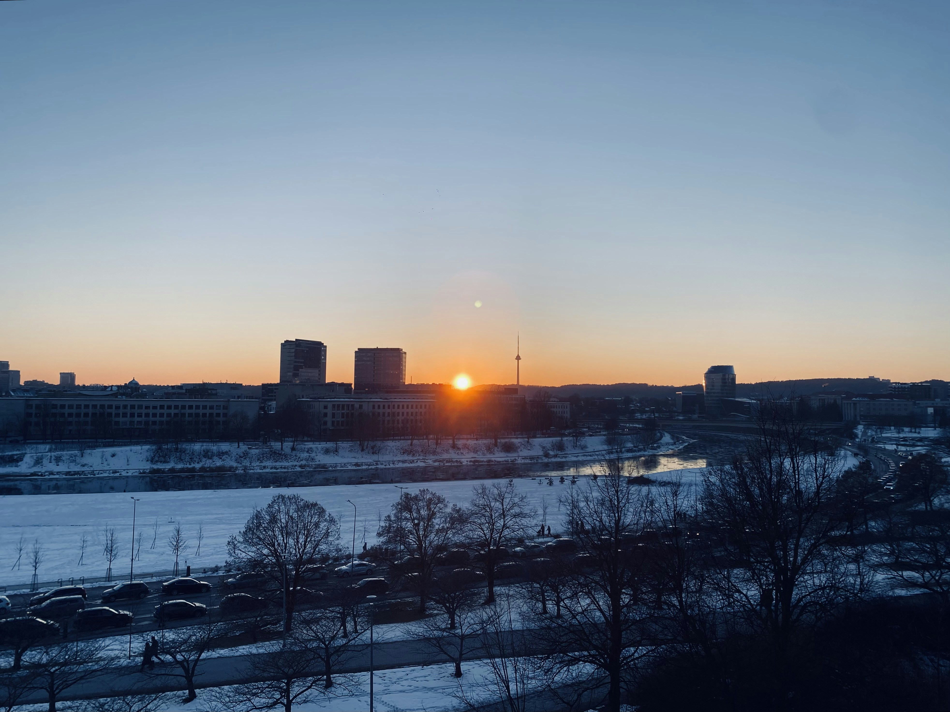 Sunrise over a snowy cityscape with buildings.