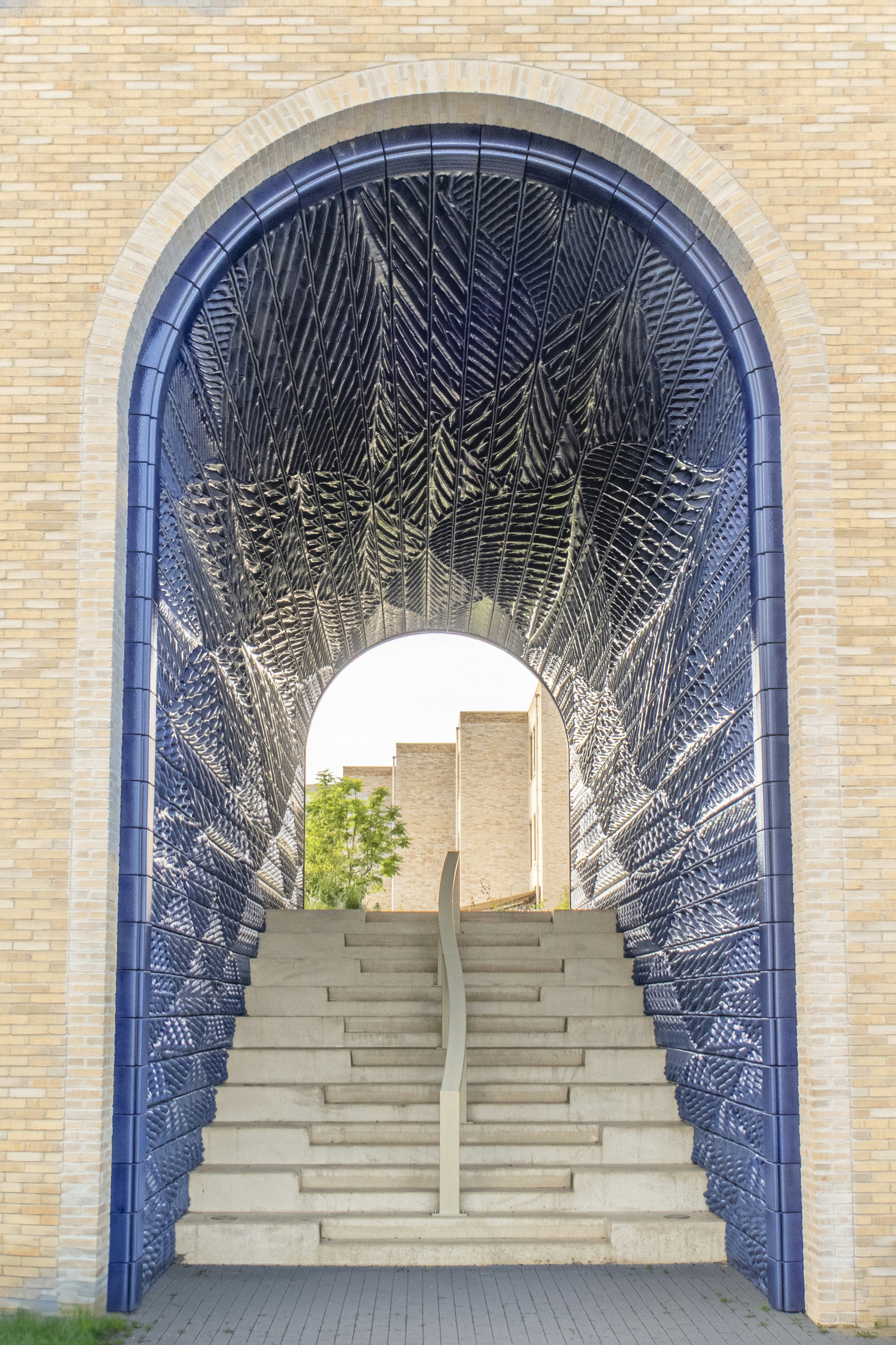 A ceramic-clad tunnel passage in Delft, Netherlands, blending modern architecture with the timeless aesthetic of traditional Delft Blue design. | A blue archway leads to steps and structures.