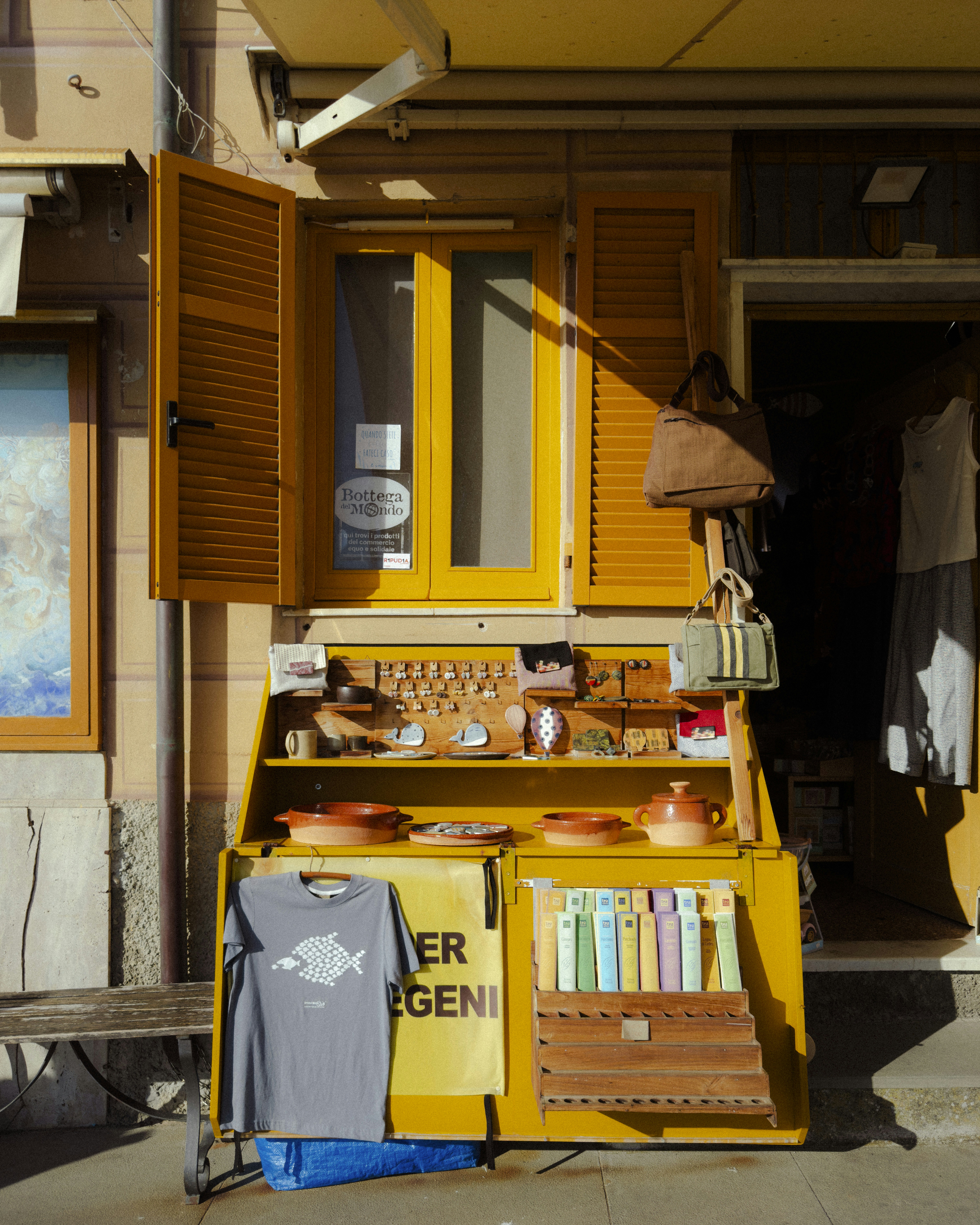 A vibrant yellow stall showcases handcrafted items and apparel, inviting passersby to explore its unique offerings.