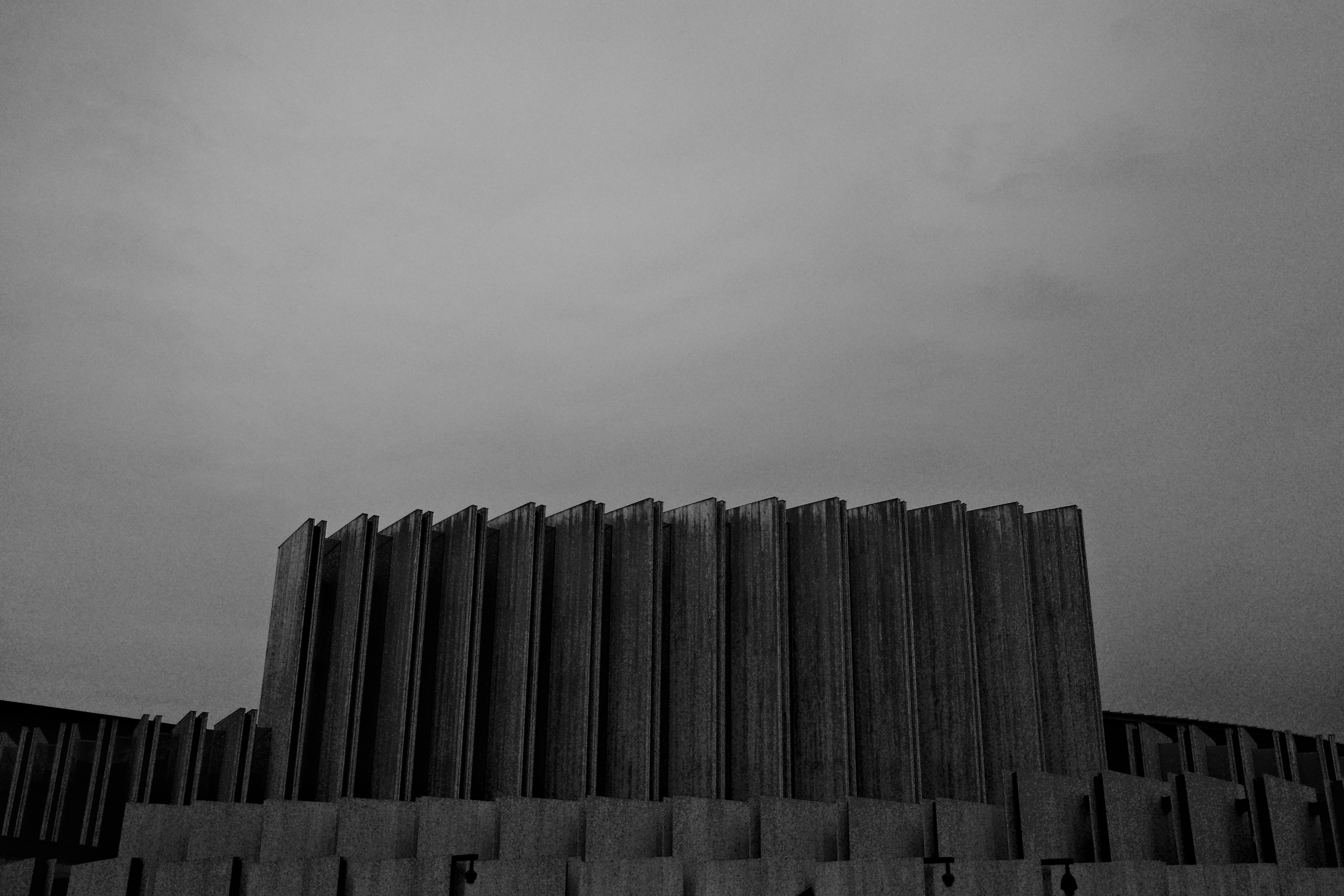 Abstract architectural structure with vertical lines against a moody sky, emphasizing geometric shapes and textures.