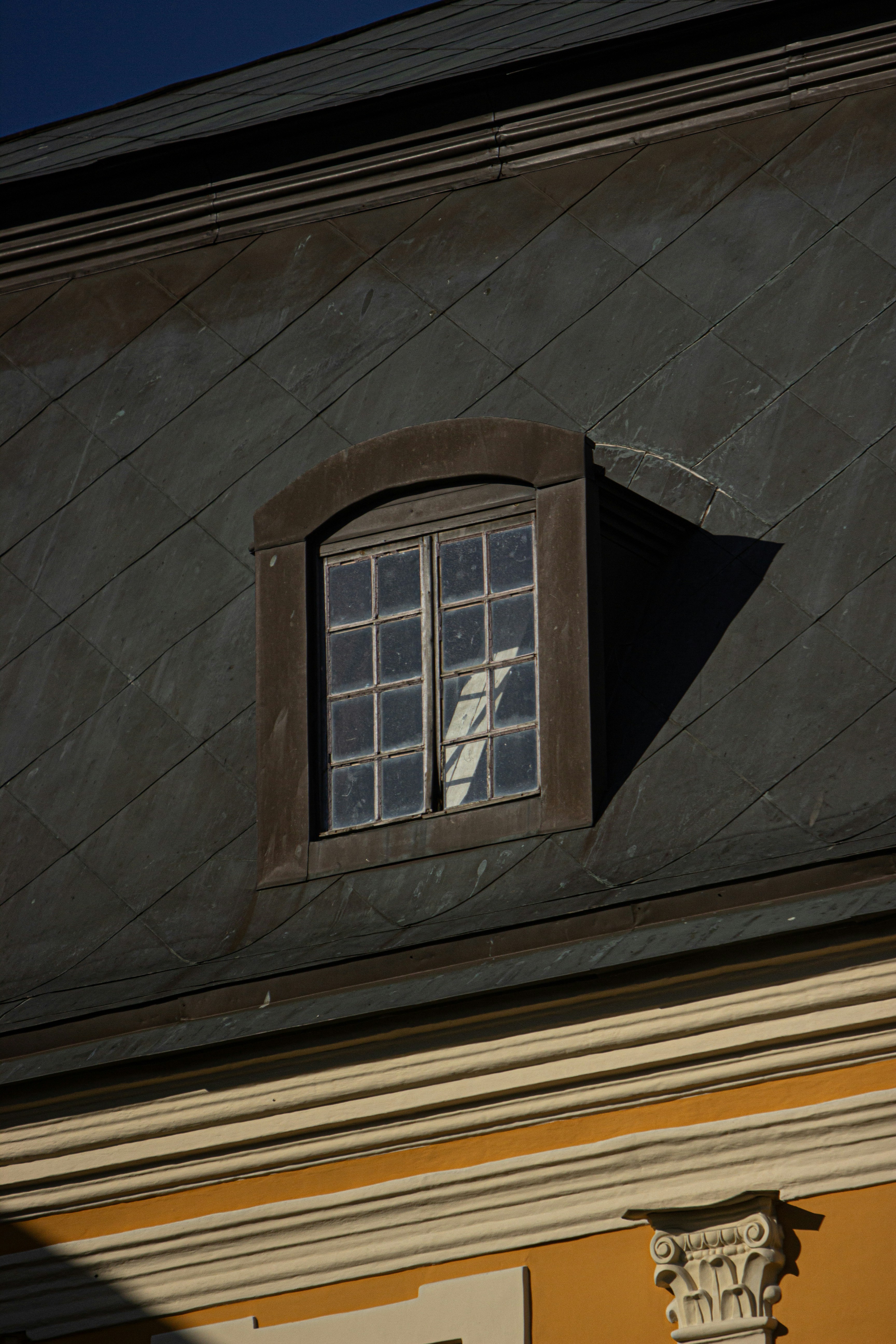 Dormer Window in a Weathered Slate Roof Under Warm Trim
