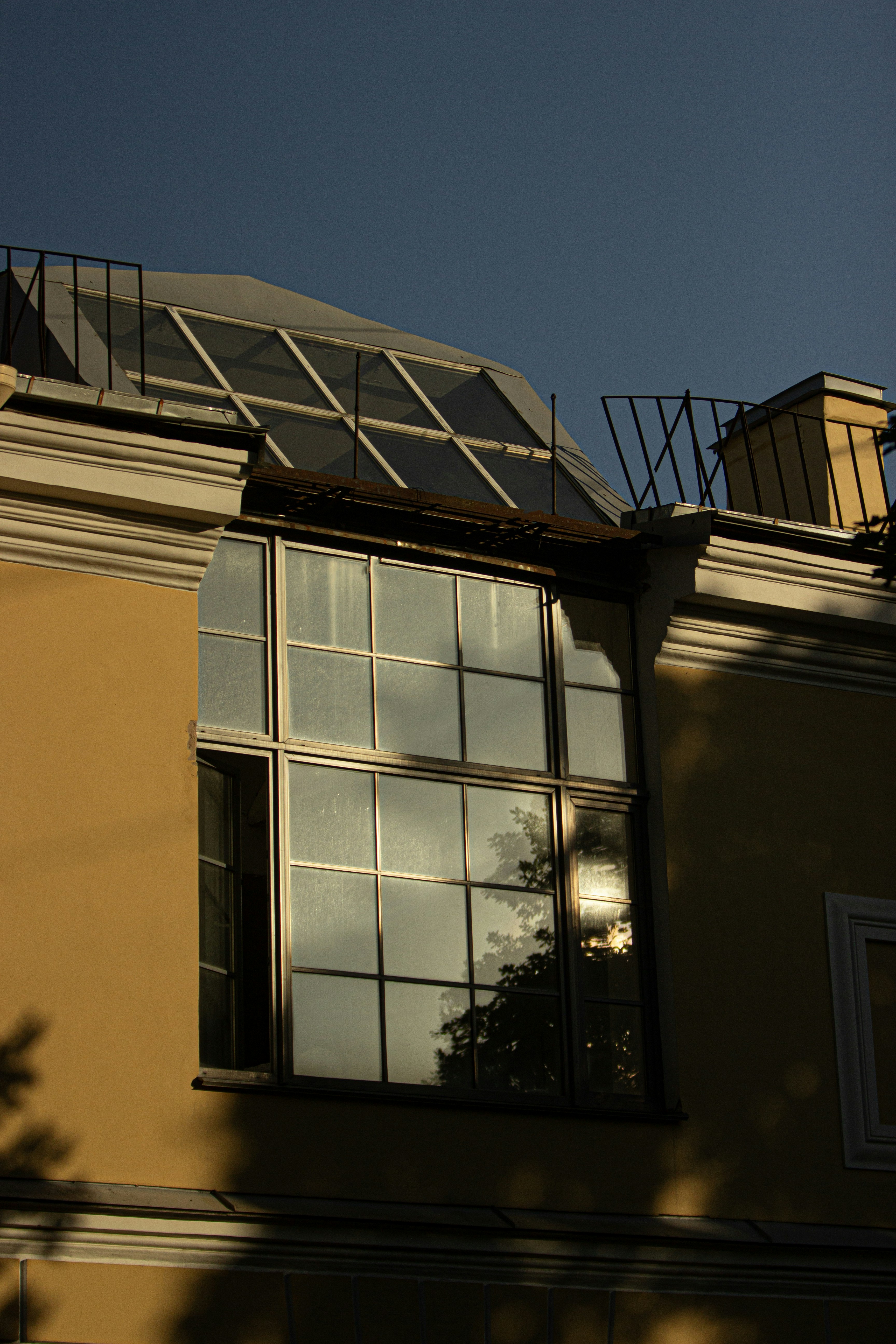 Last-Light Window on a Yellow Facade: Grid, Glass, and Shadows