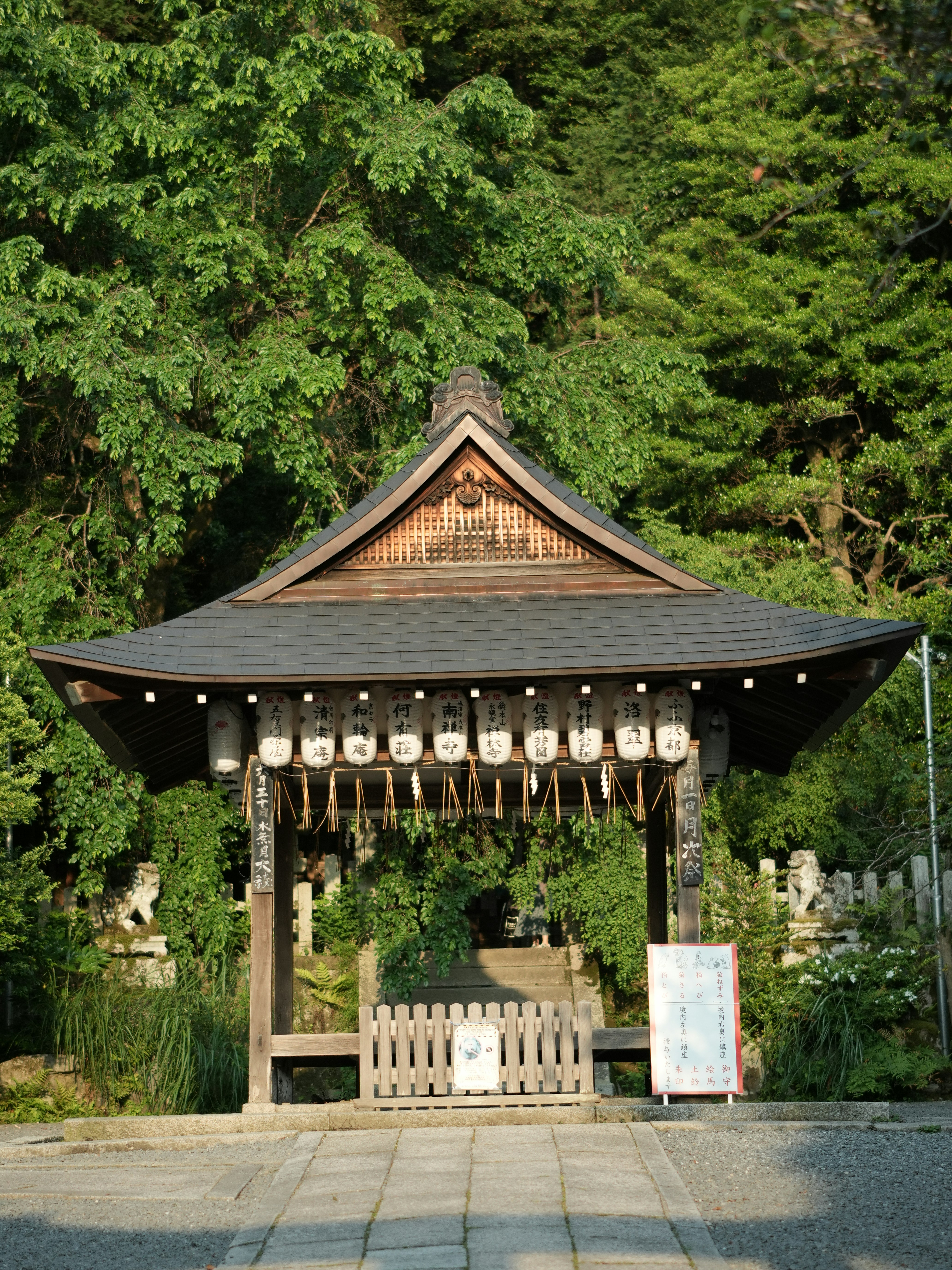 Traditional Japanese torii gate adorned with lanterns, framed by lush greenery, inviting visitors into a serene spiritual space.