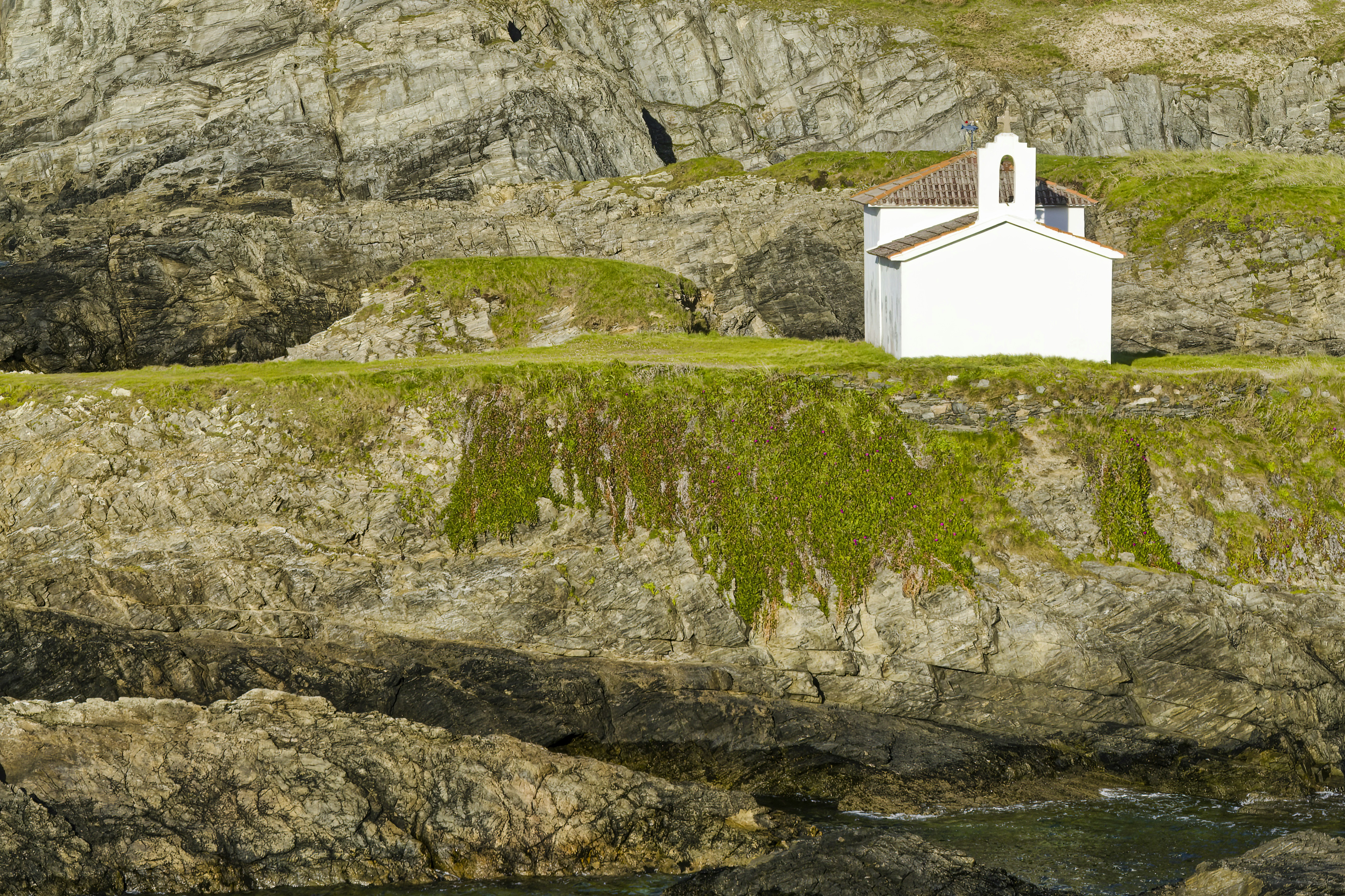 A small white church perched on rocky cliffs. photo – Free Architecture ...