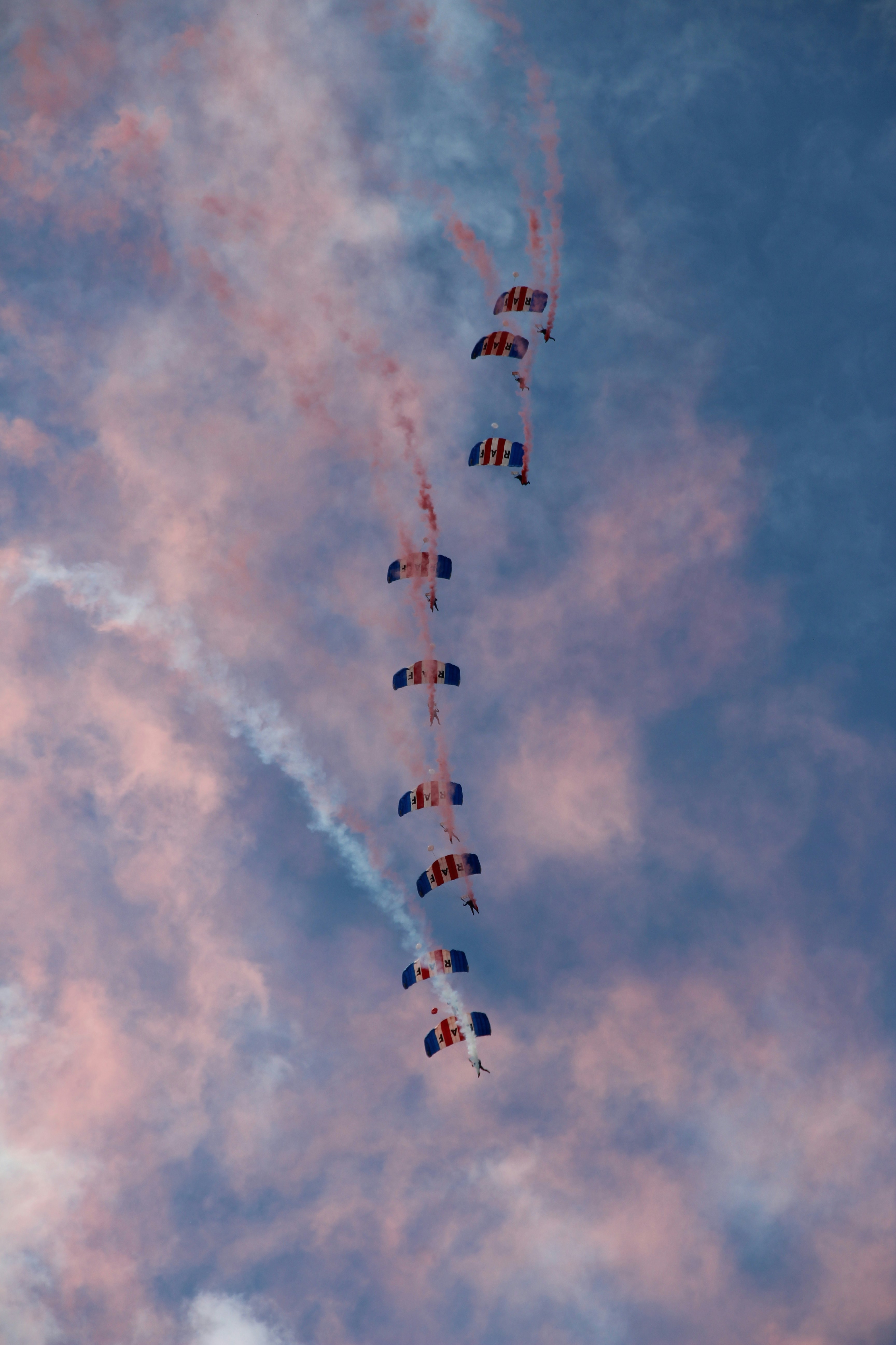 Parallel Sky Parade: A Row of Colorful Parachutes Over a Pink-Tinted Sky