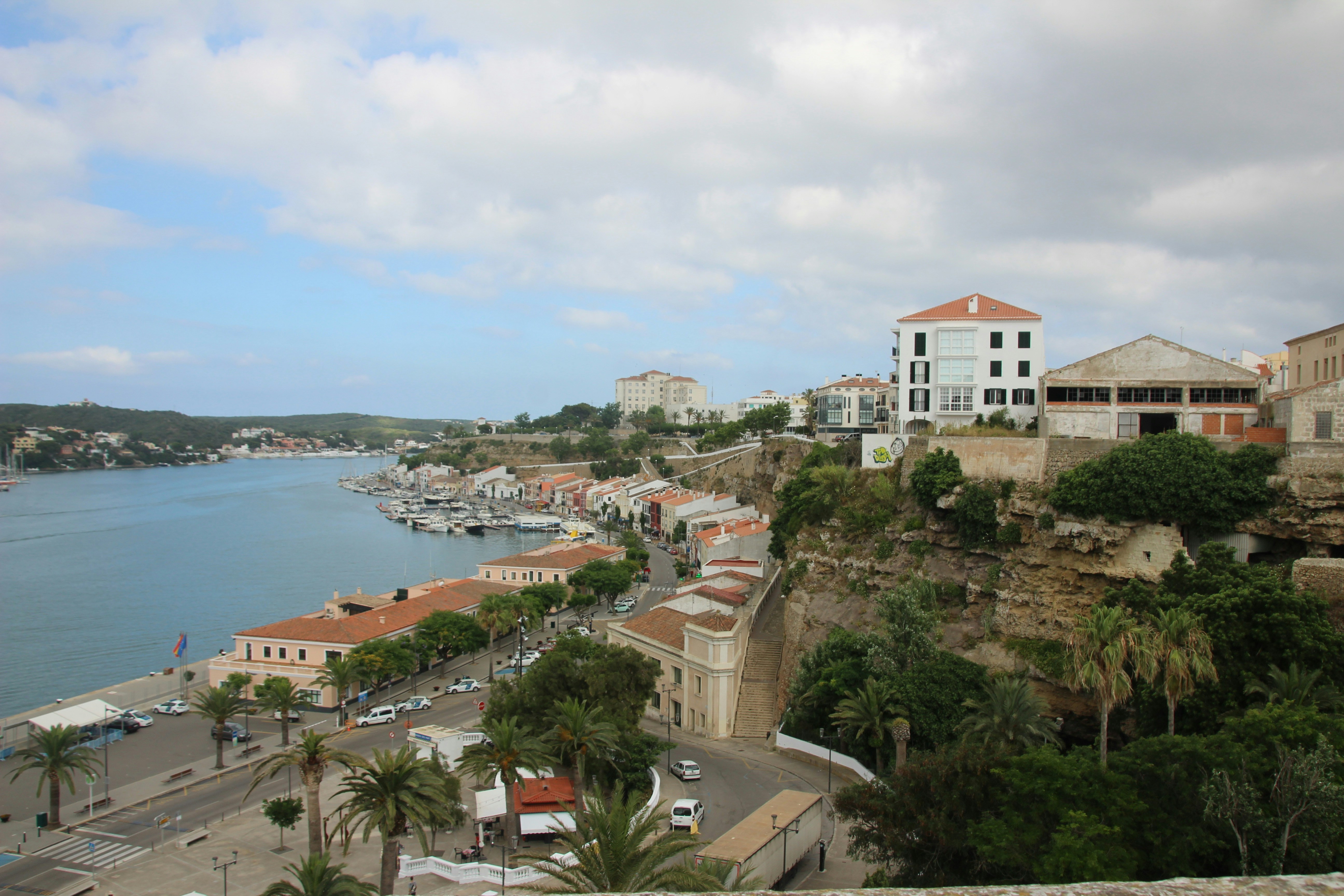 Coastal town with colorful buildings lining the harbor, surrounded by lush greenery and a serene waterway.