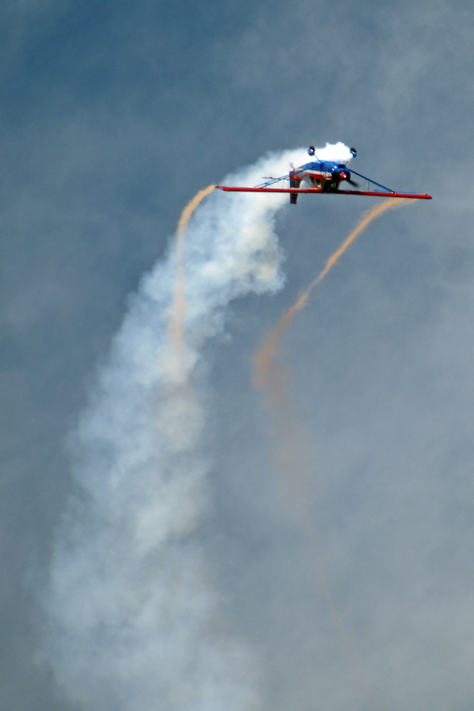 Red Wing in Blue: Aerial Acrobat Leaving Twin Vapor Arcs