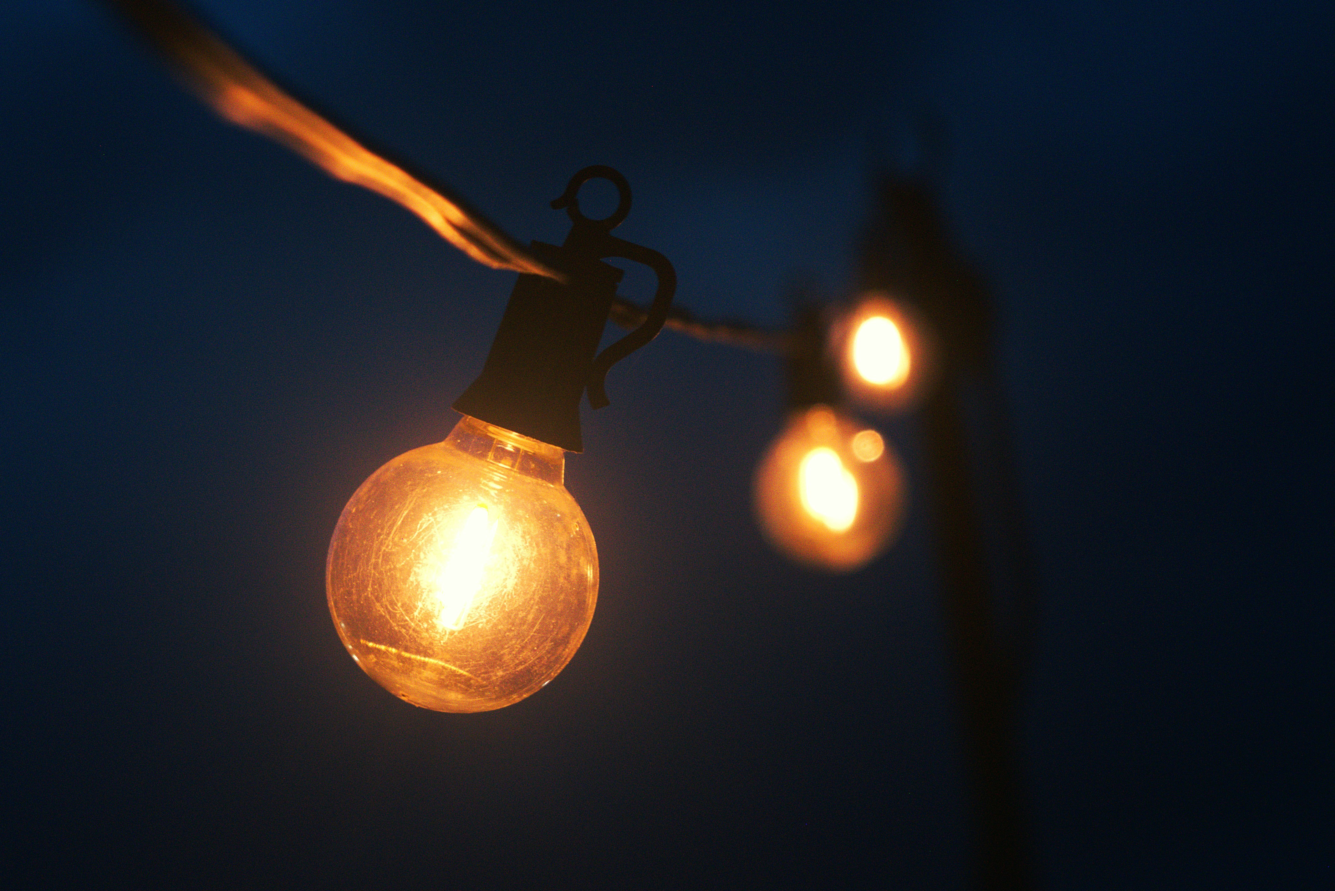 Lit string lights glow against a dark background. photo – Free Night ...