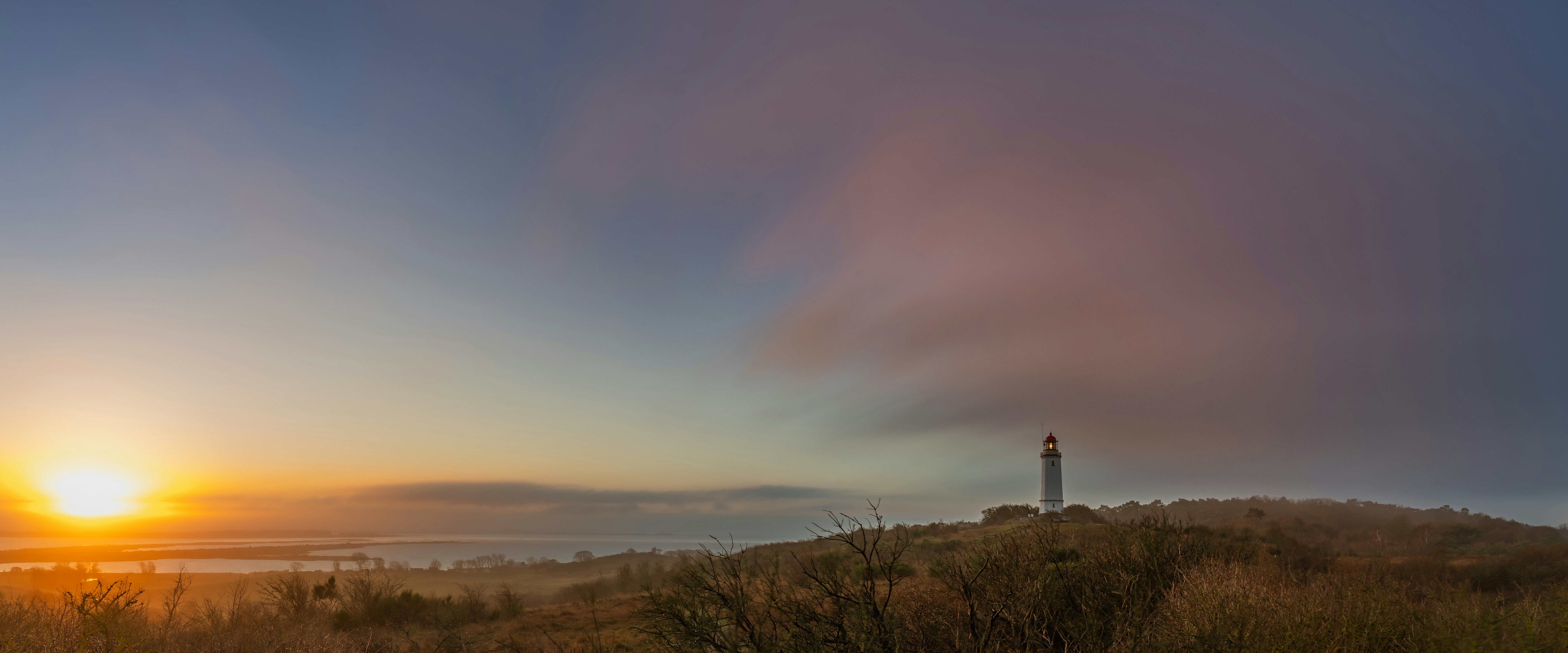 Lighthouse at Dusk: Wind-Worn Dunes and a Quiet Sea Light