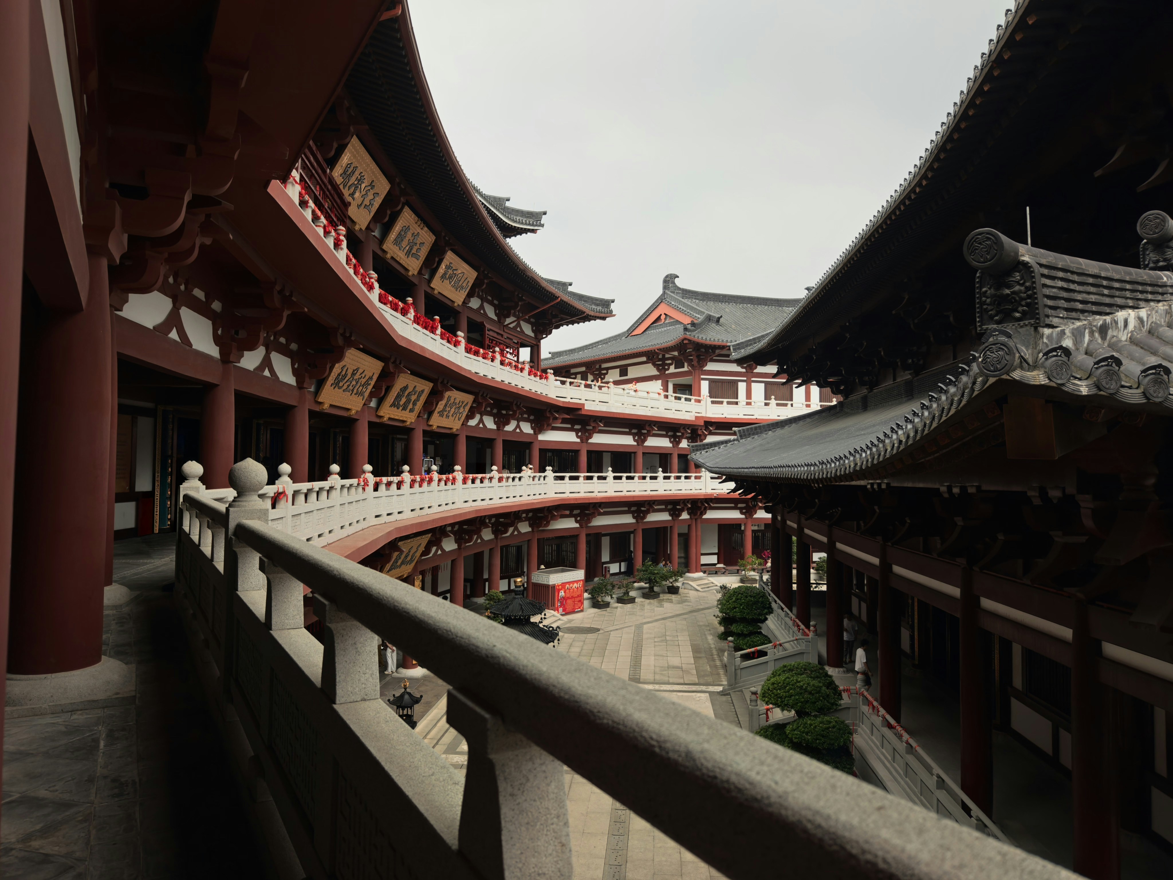 Elegant traditional architecture featuring curved balconies and intricate roof designs in a serene courtyard setting.