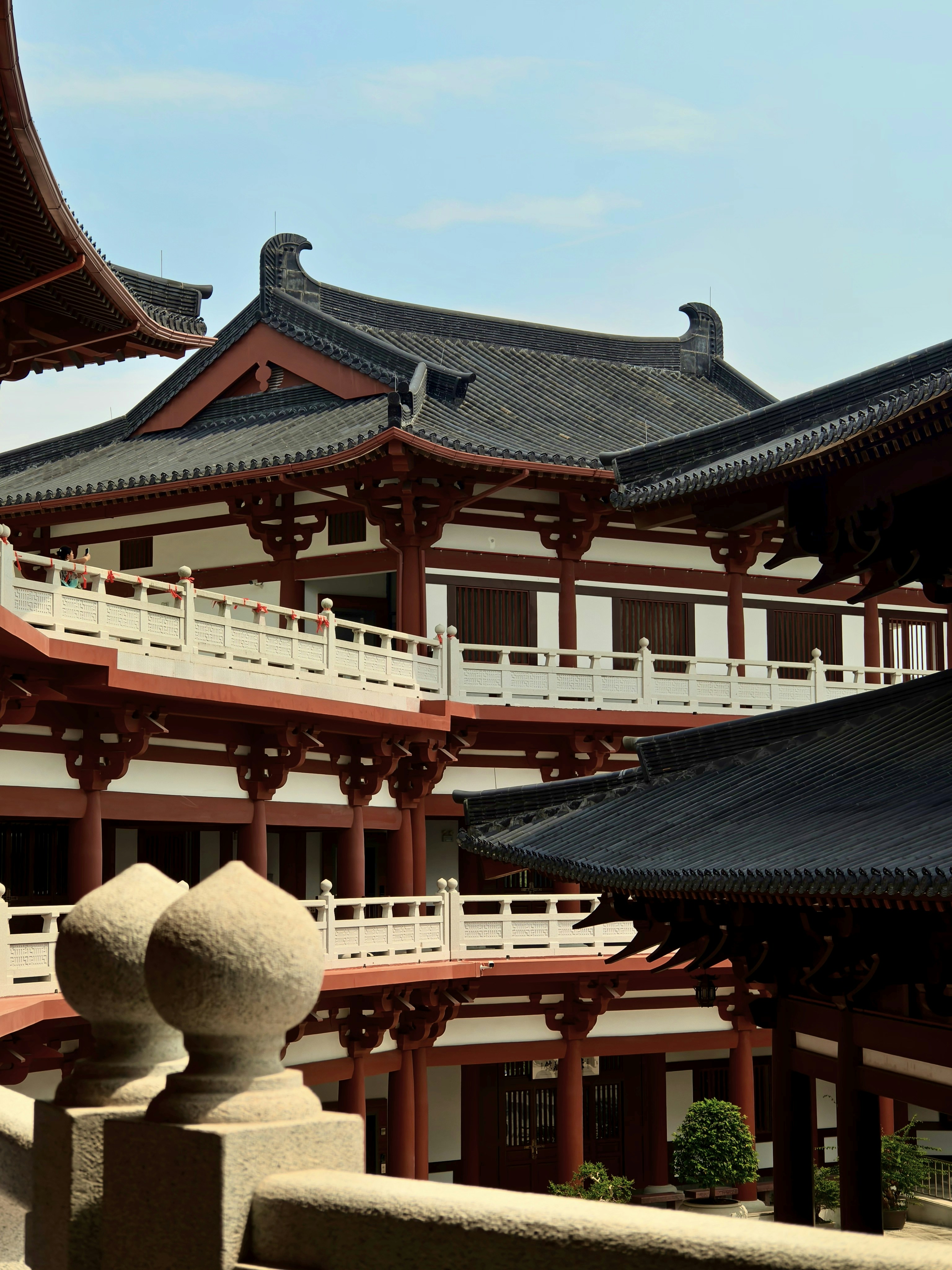 Intricate traditional architecture featuring multiple tiers and ornate roofs, showcasing a serene courtyard with lush greenery.