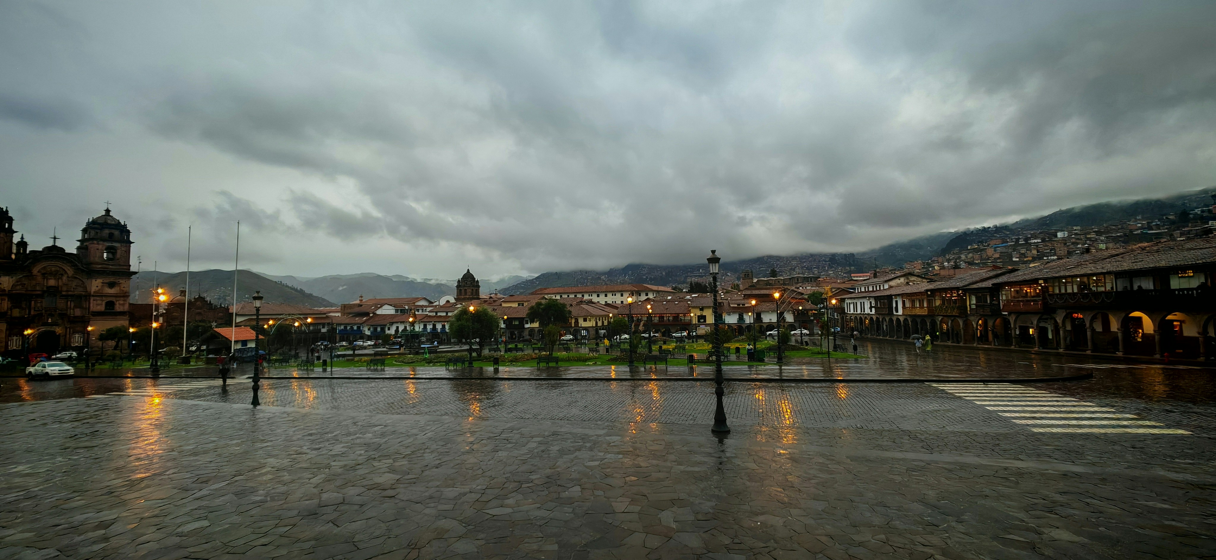 Rain falls on a city square under overcast skies.