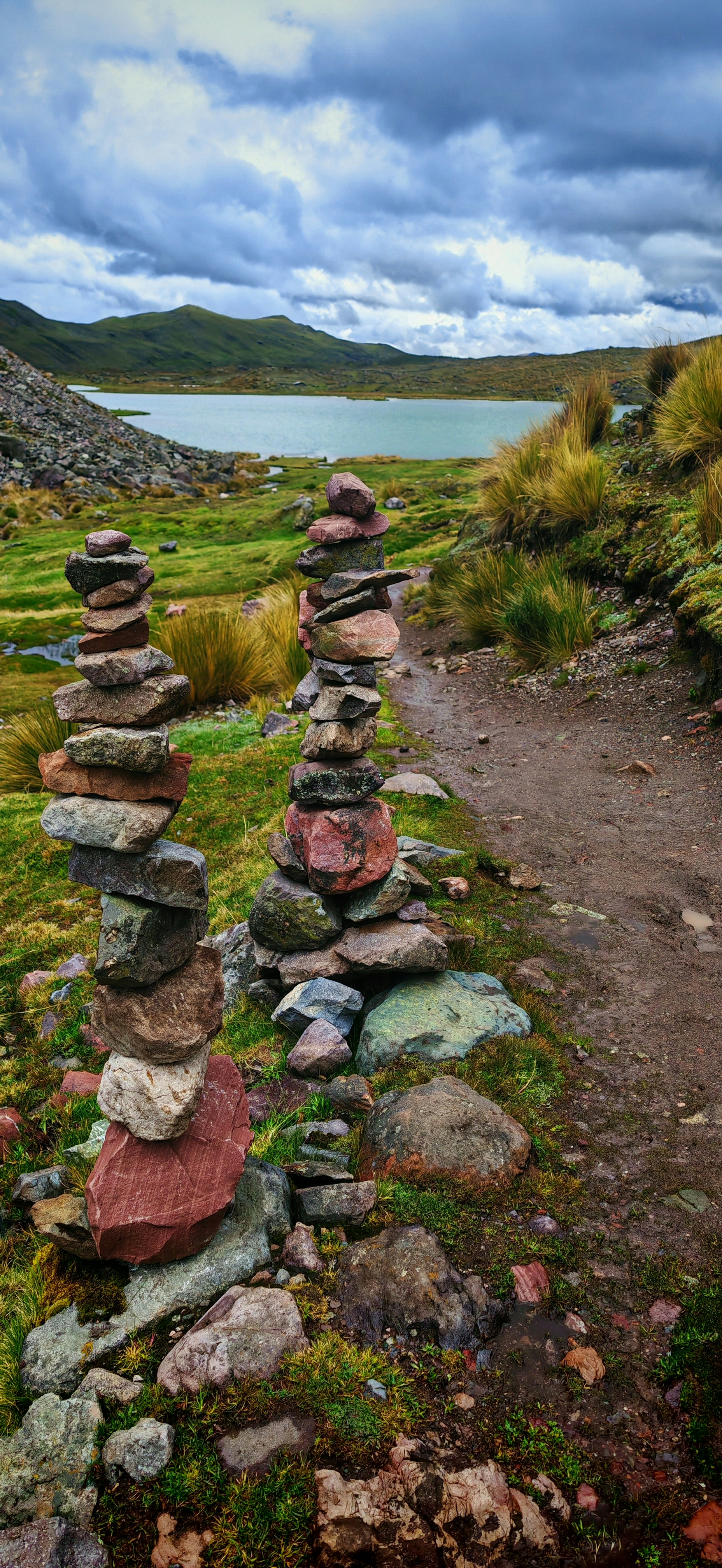 Stone cairns lead to a lake in a scenic landscape.