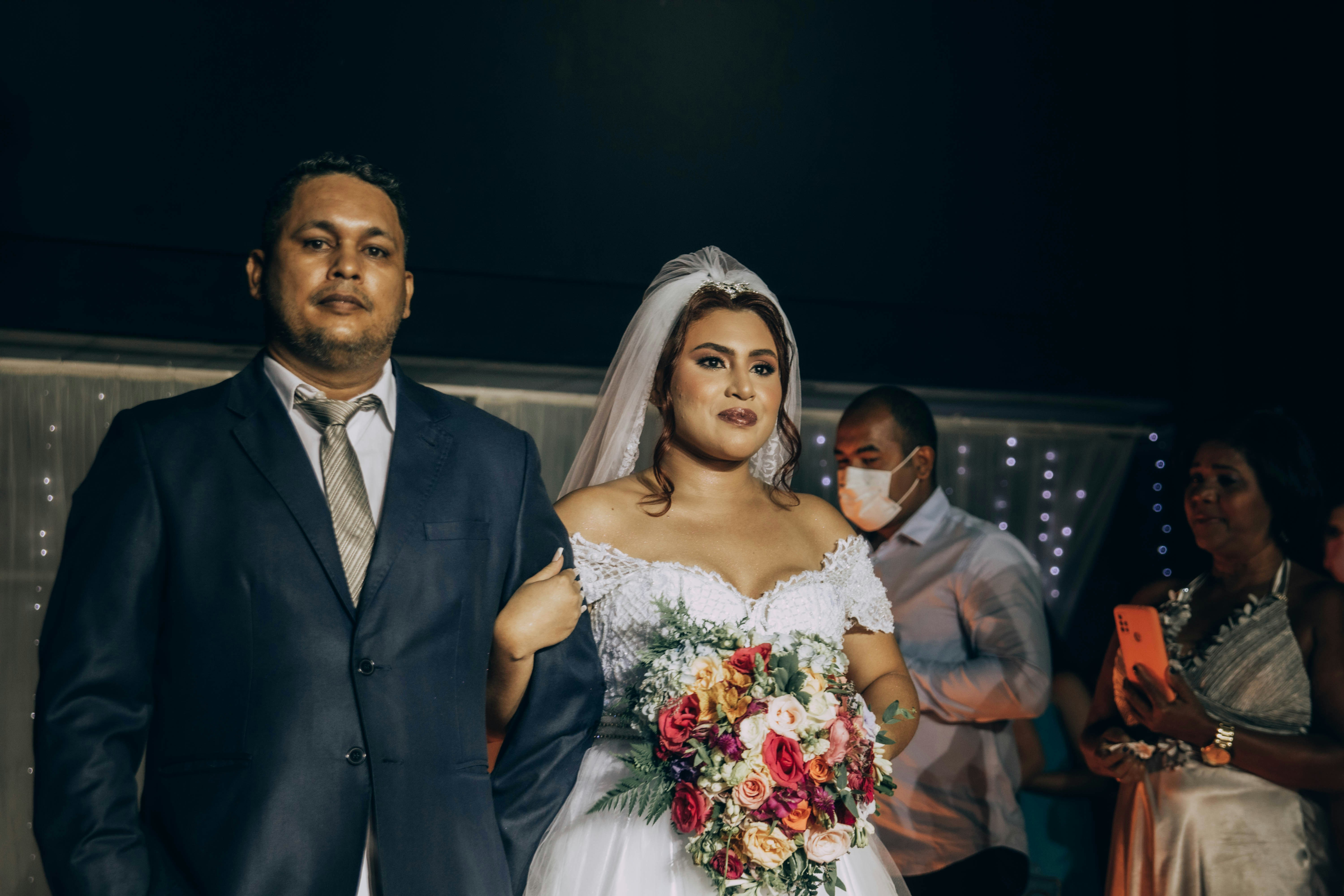 Bride and groom walking down the aisle, surrounded by friends and family, with vibrant floral arrangements in hand. The scene captures the essence of a joyful wedding ceremony.