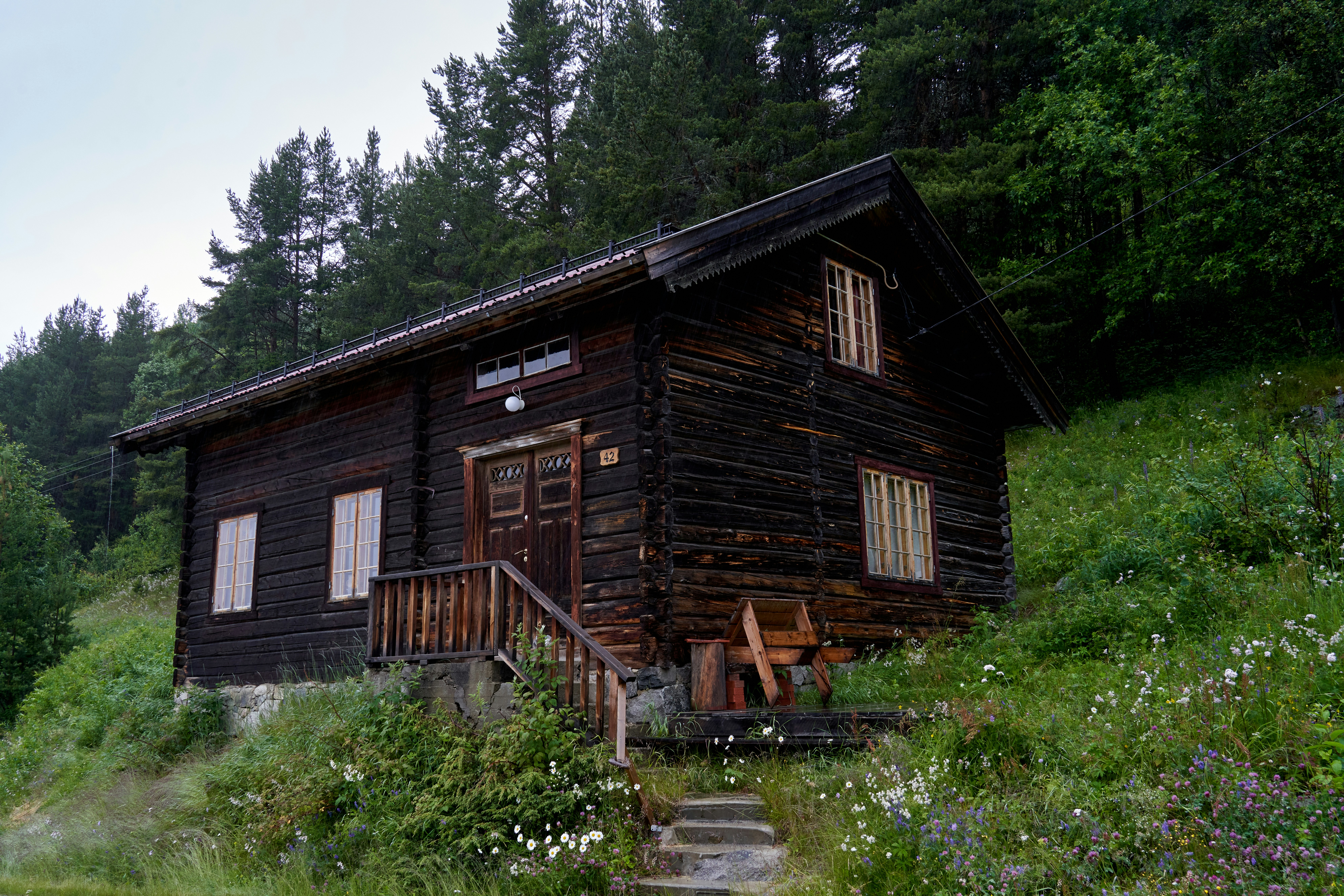 A wooden cabin sits on a grassy hillside. photo – Free Outdoor Image on ...
