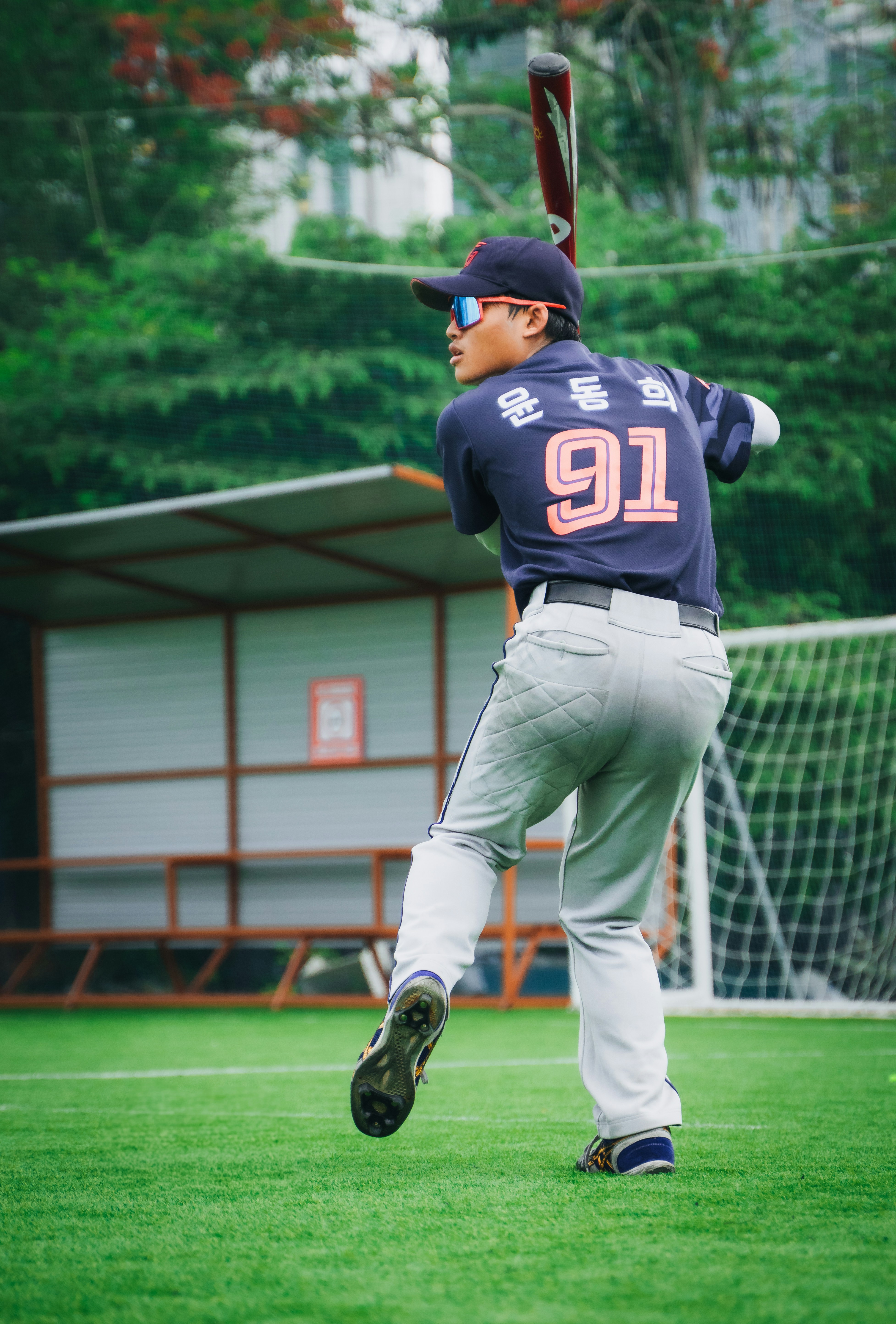 Baseball player in a dark jersey prepares to swing his bat on a lush green field, showcasing focus and readiness.