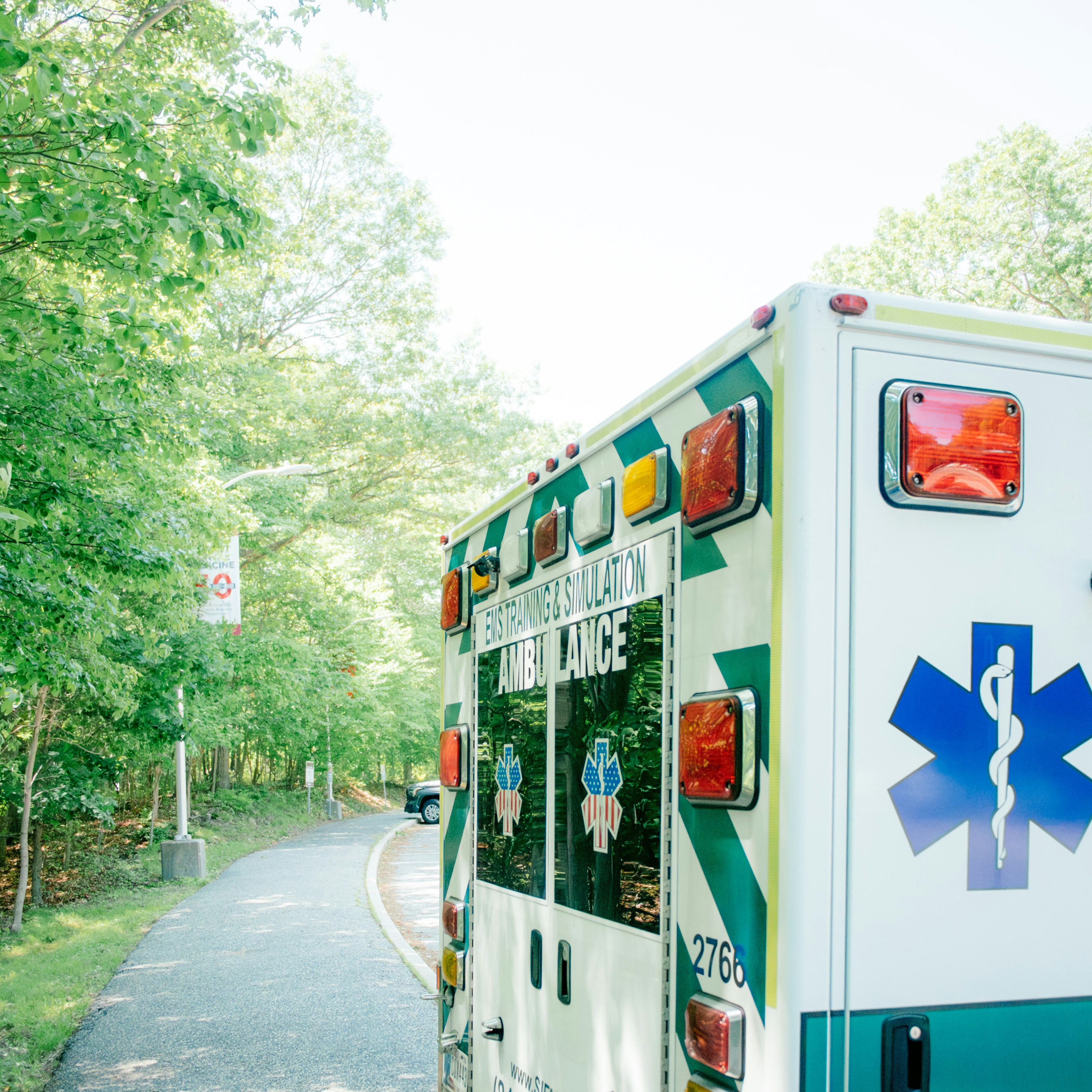 An ambulance drives down a scenic path. photo – Free Truck Image on ...