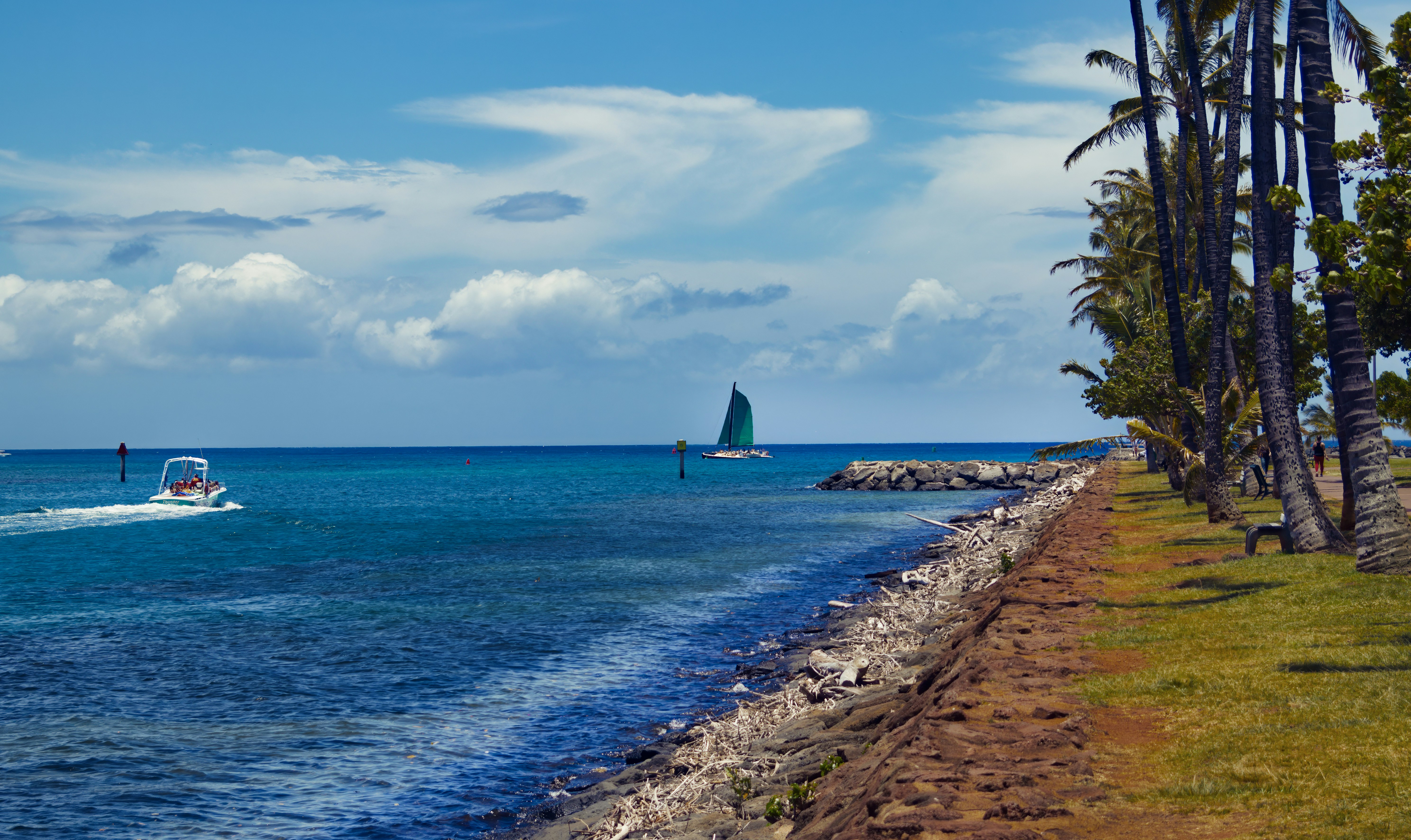Speed and Sail | Boats sail along a tropical coastline.