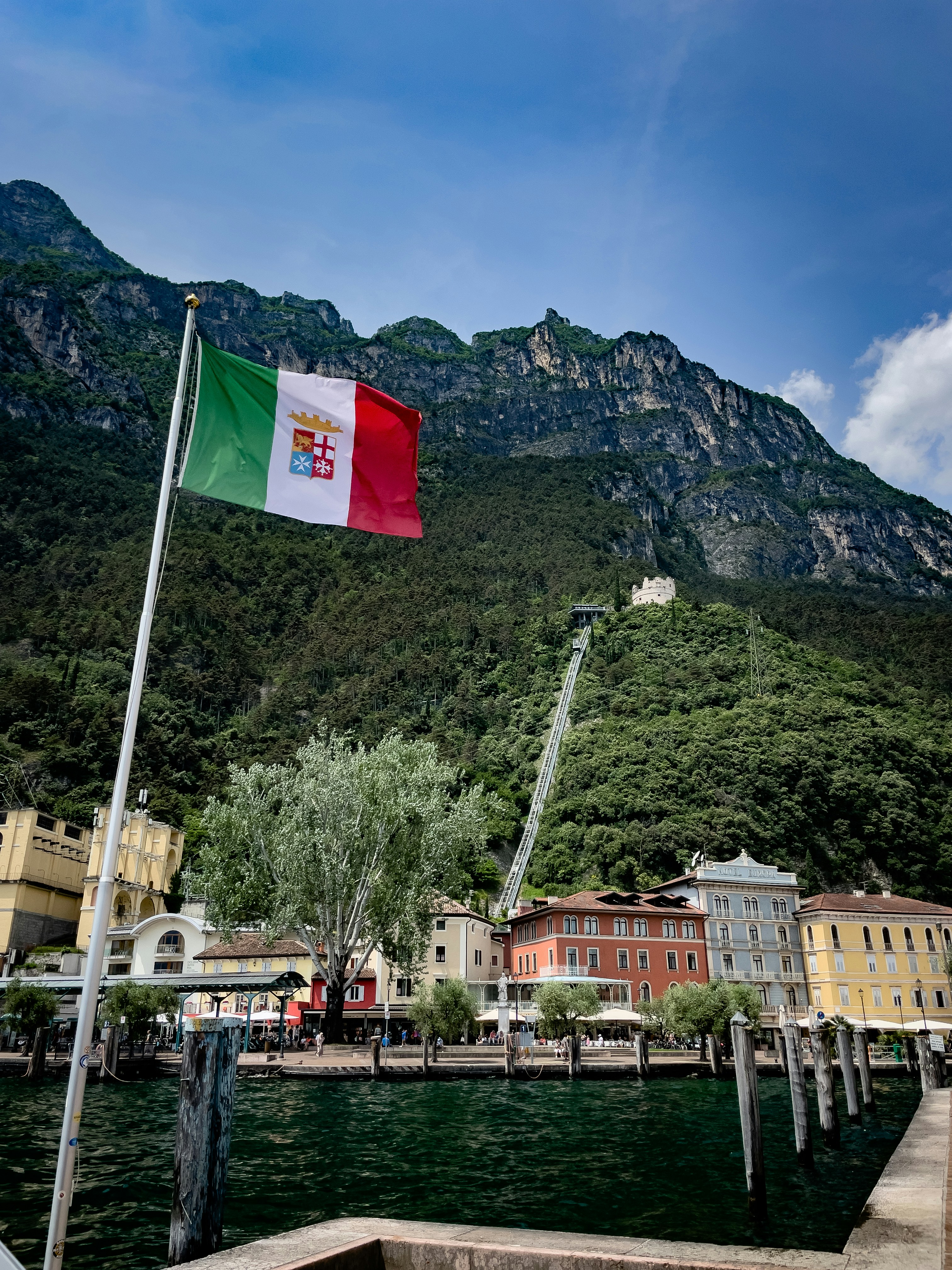 Flag over the Alpine Waterfront: Italian Tricolor Framing a Mountain Village